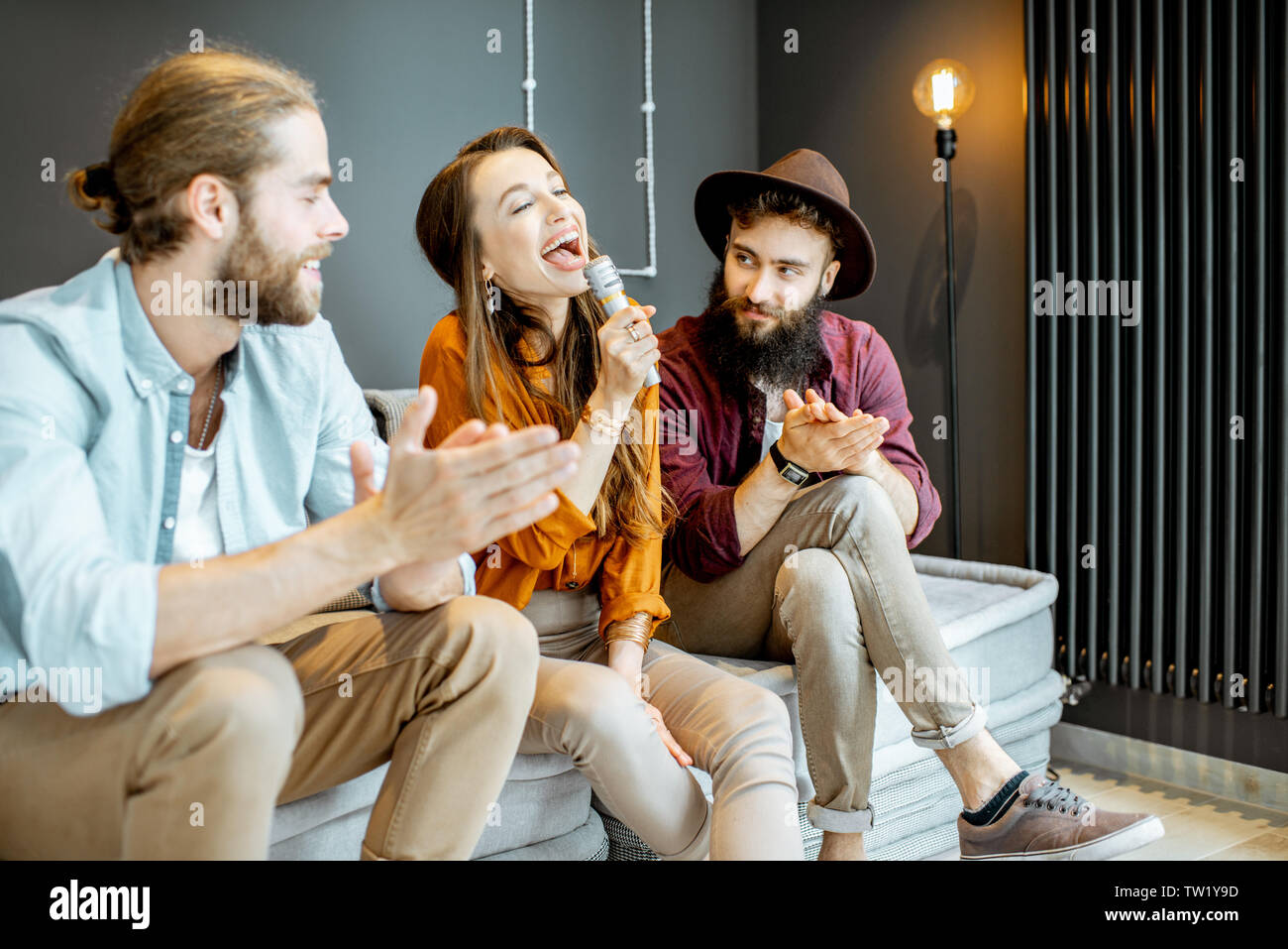 Young and cheerful friends singing with microphone while playing ...