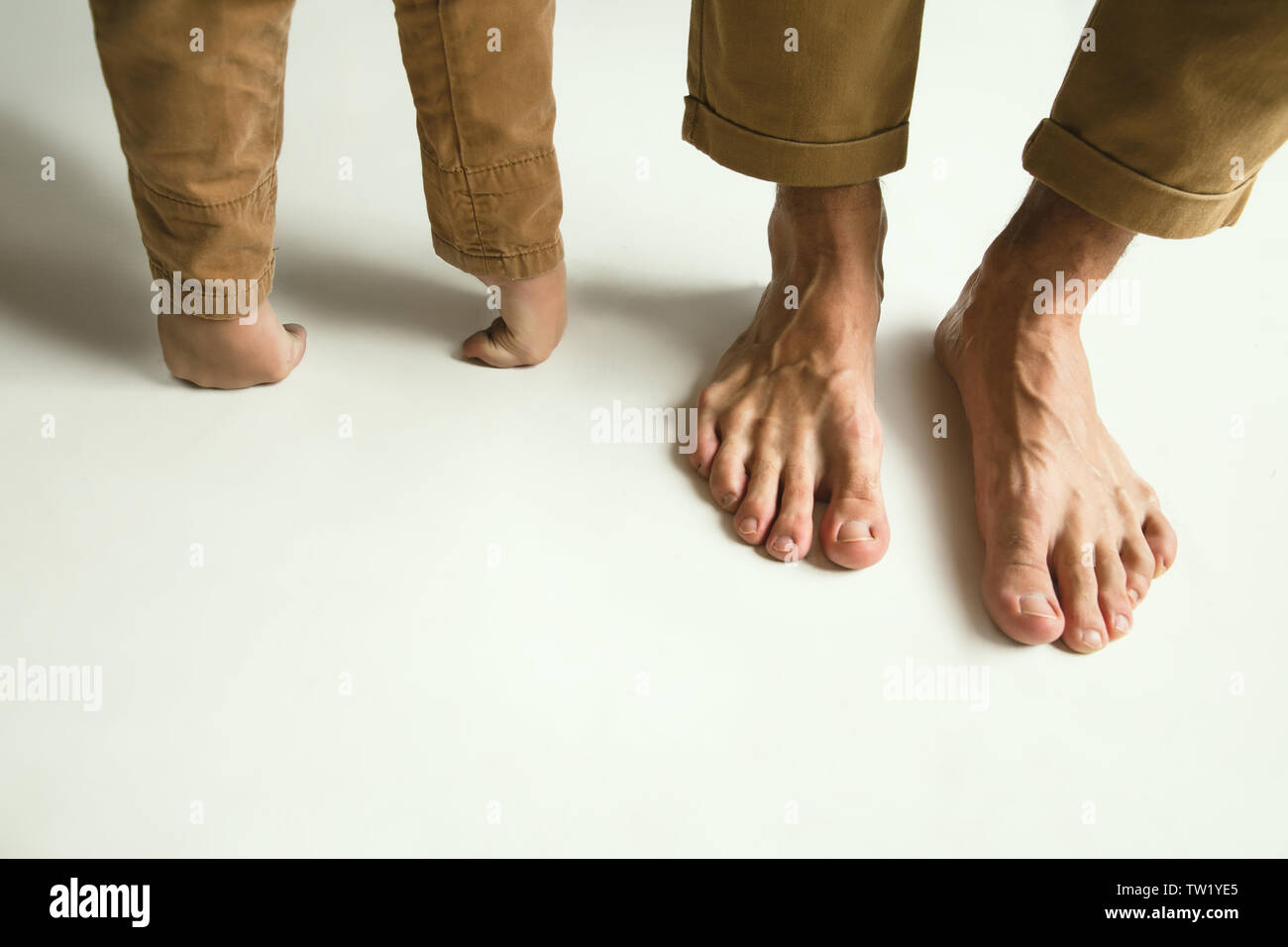 Family's legs on white studio background. Barefoot dad and son standing ...