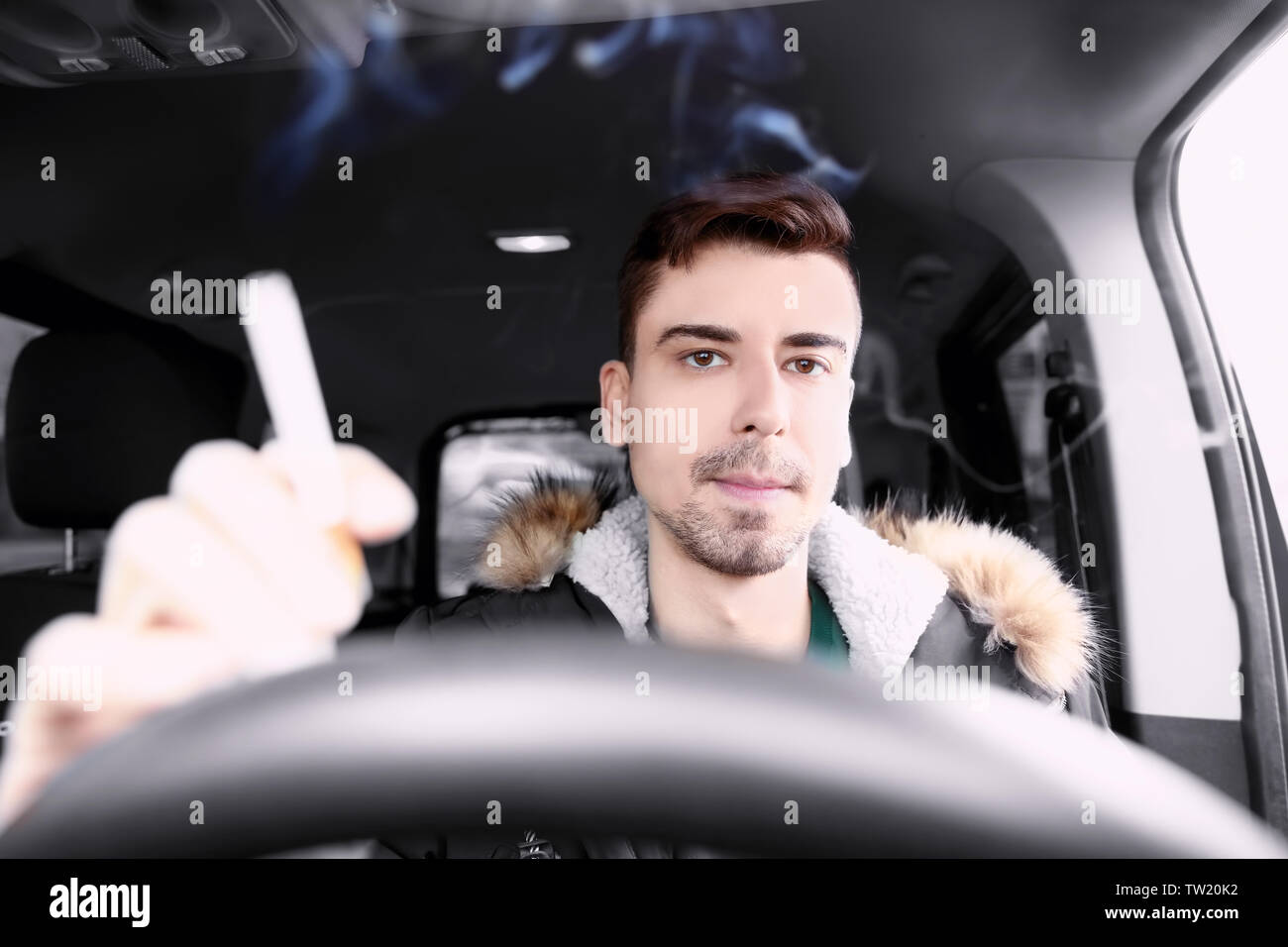 Young man driving a car and smoking cigarette Stock Photo - Alamy