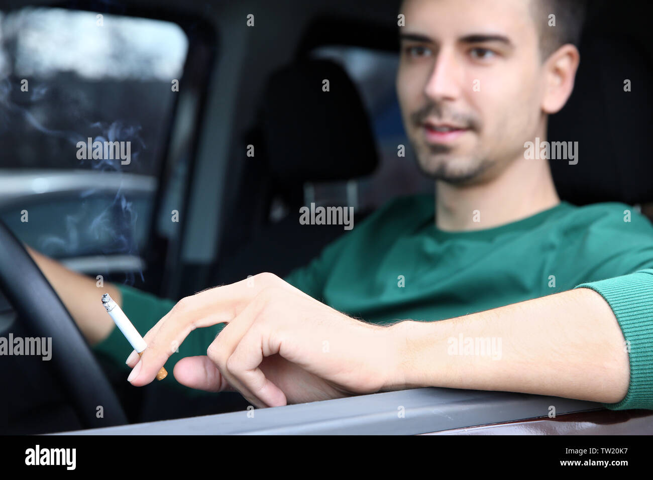 Young man driving a car and smoking cigarette Stock Photo - Alamy