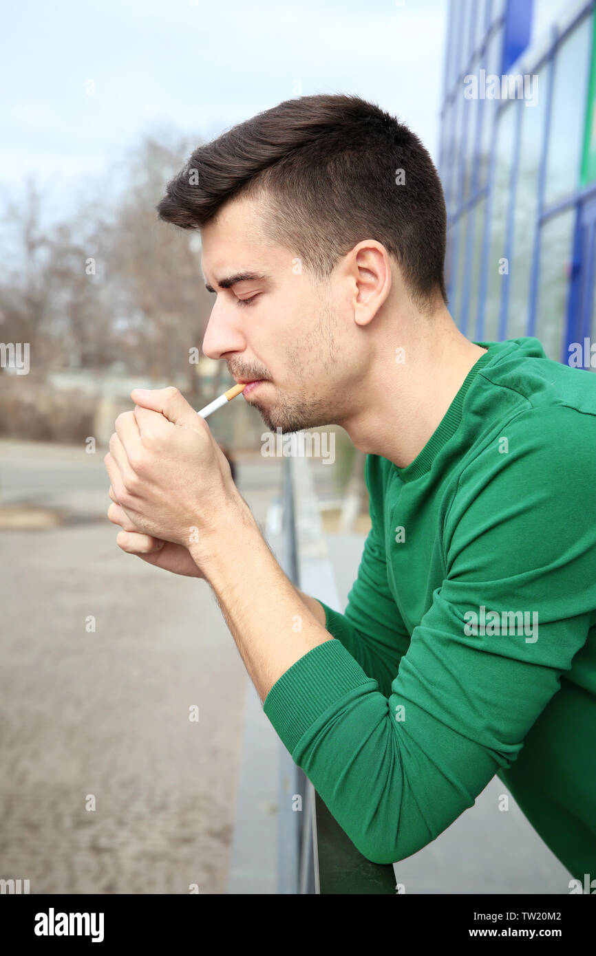 Young man smoking cigarette outdoors Stock Photo - Alamy