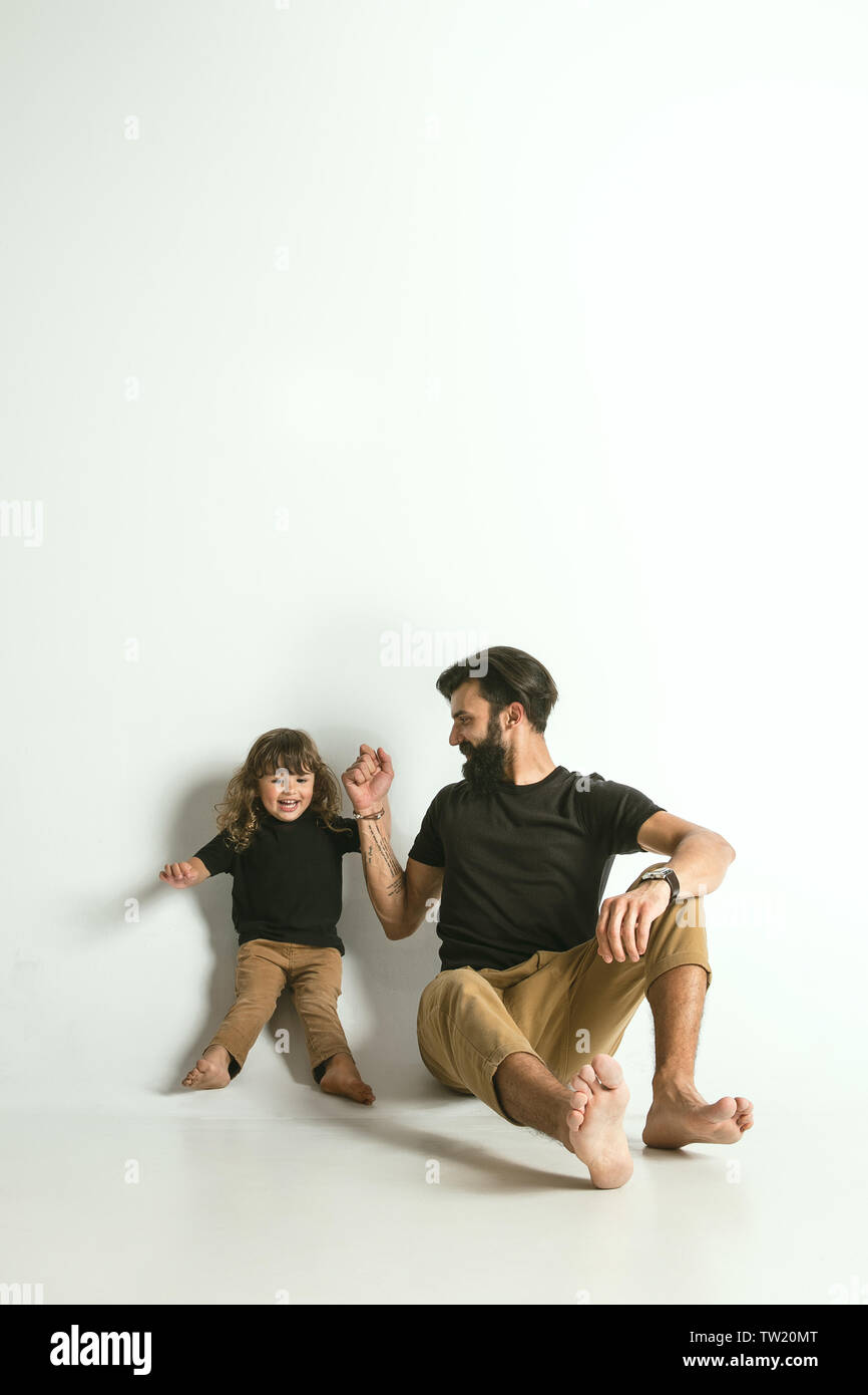 Father playing with young son against white studio background. Young ...