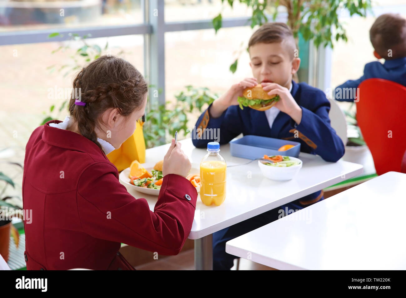 Children sitting at cafeteria table while eating lunch Stock Photo - Alamy