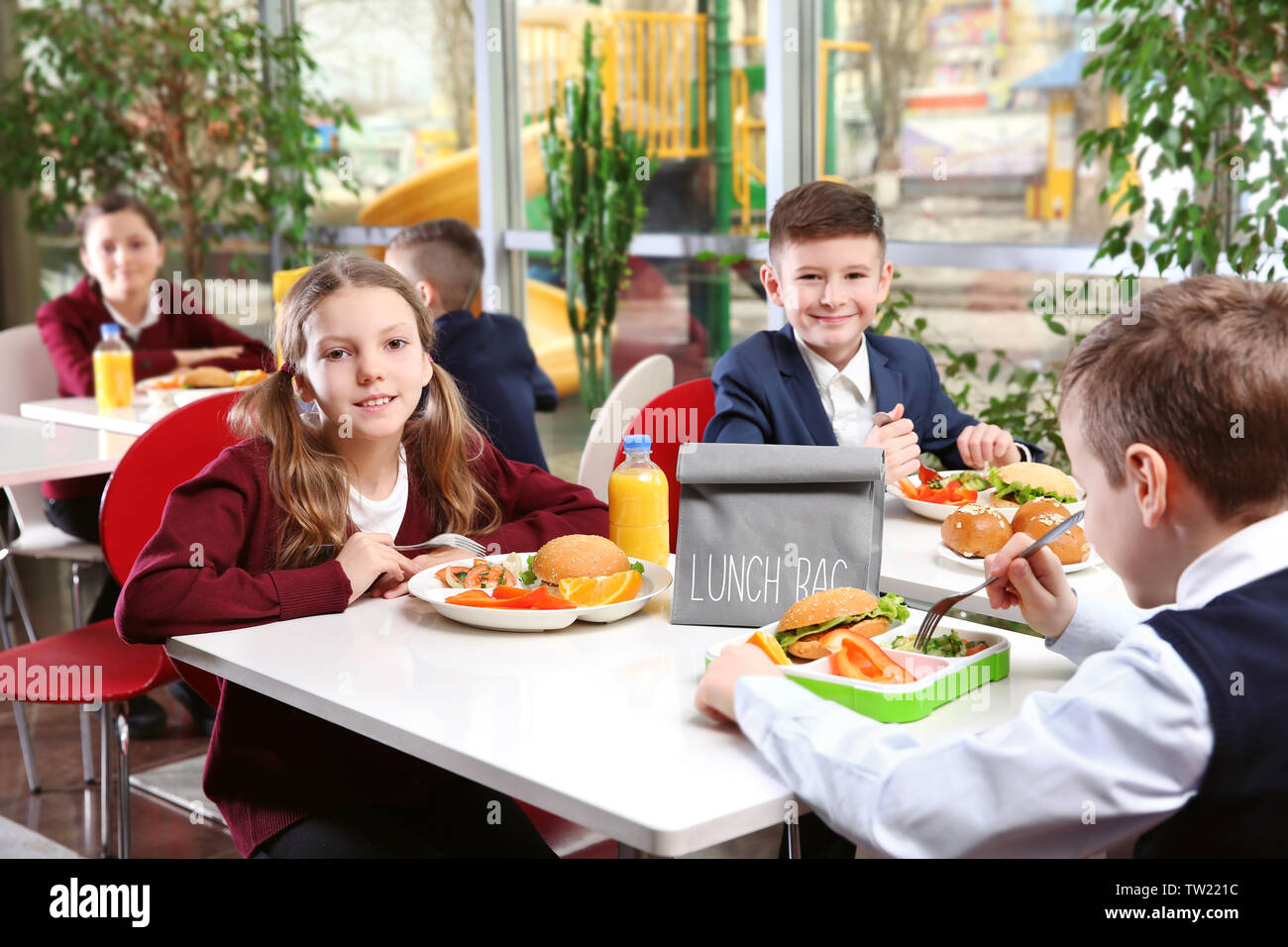 Children sitting at cafeteria table while eating lunch Stock Photo - Alamy