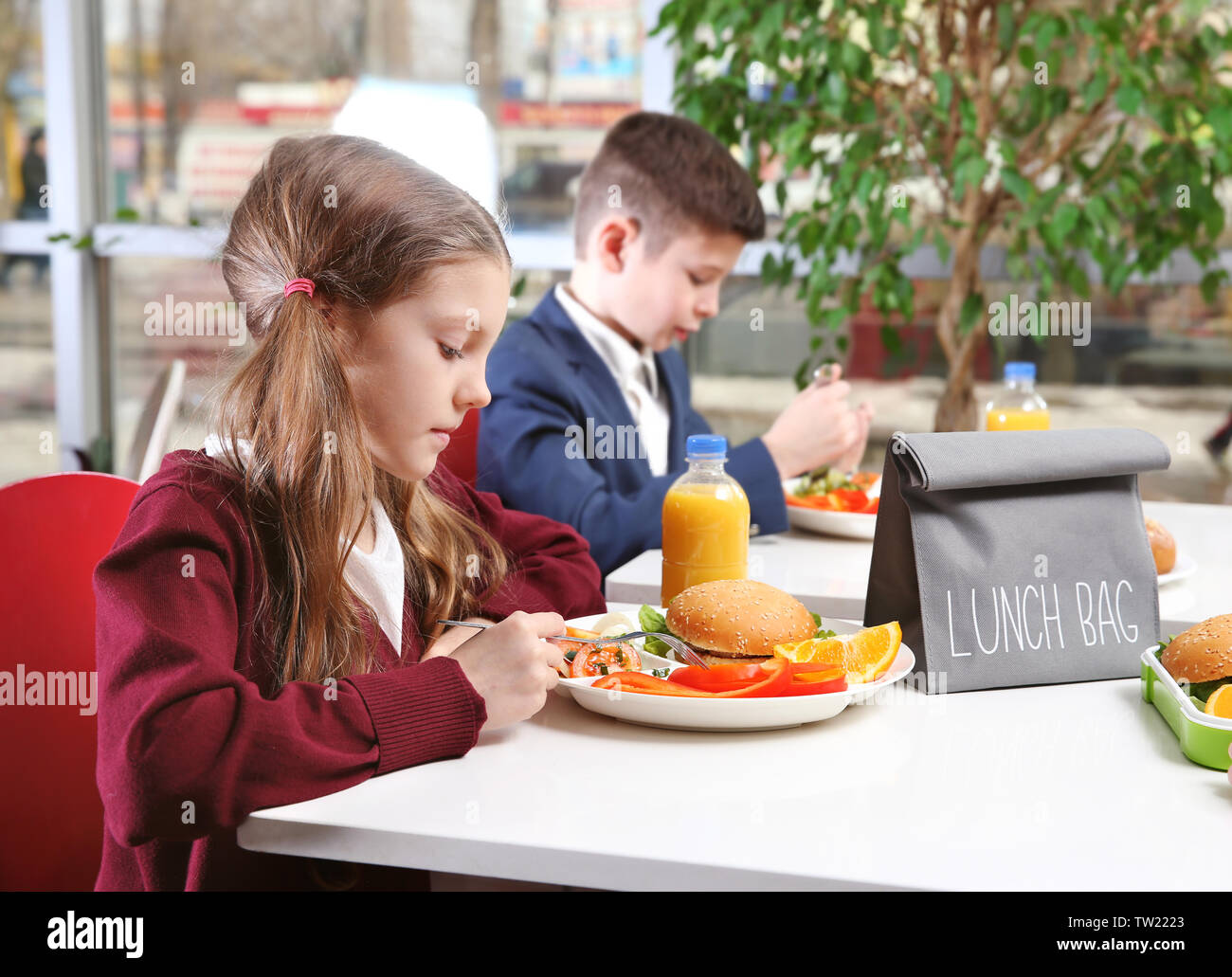 Children sitting at cafeteria table while eating lunch Stock Photo - Alamy