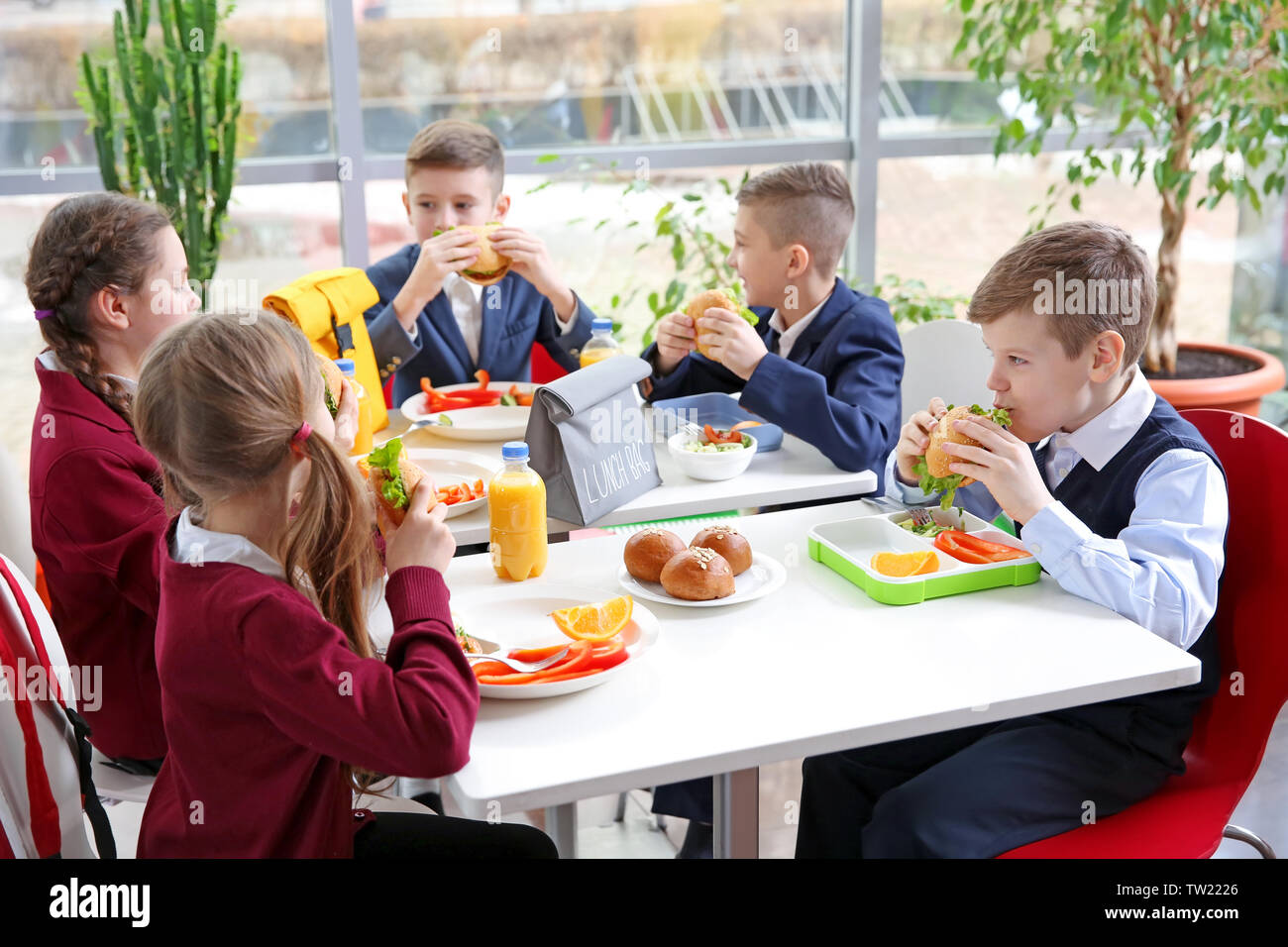 Children sitting at cafeteria table while eating lunch Stock Photo - Alamy