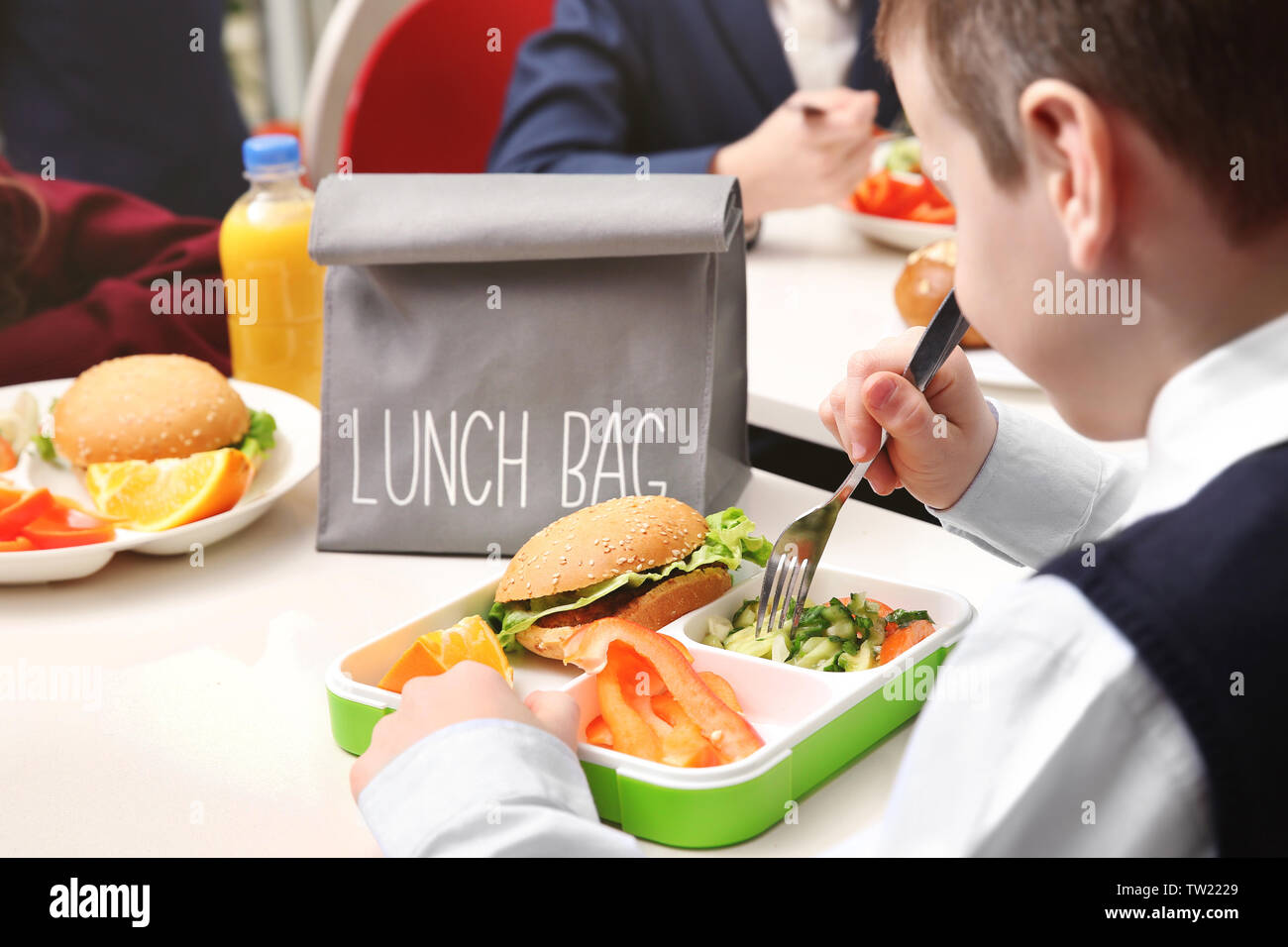 School boy eating delicious homemade food from lunch box in cafeteria ...