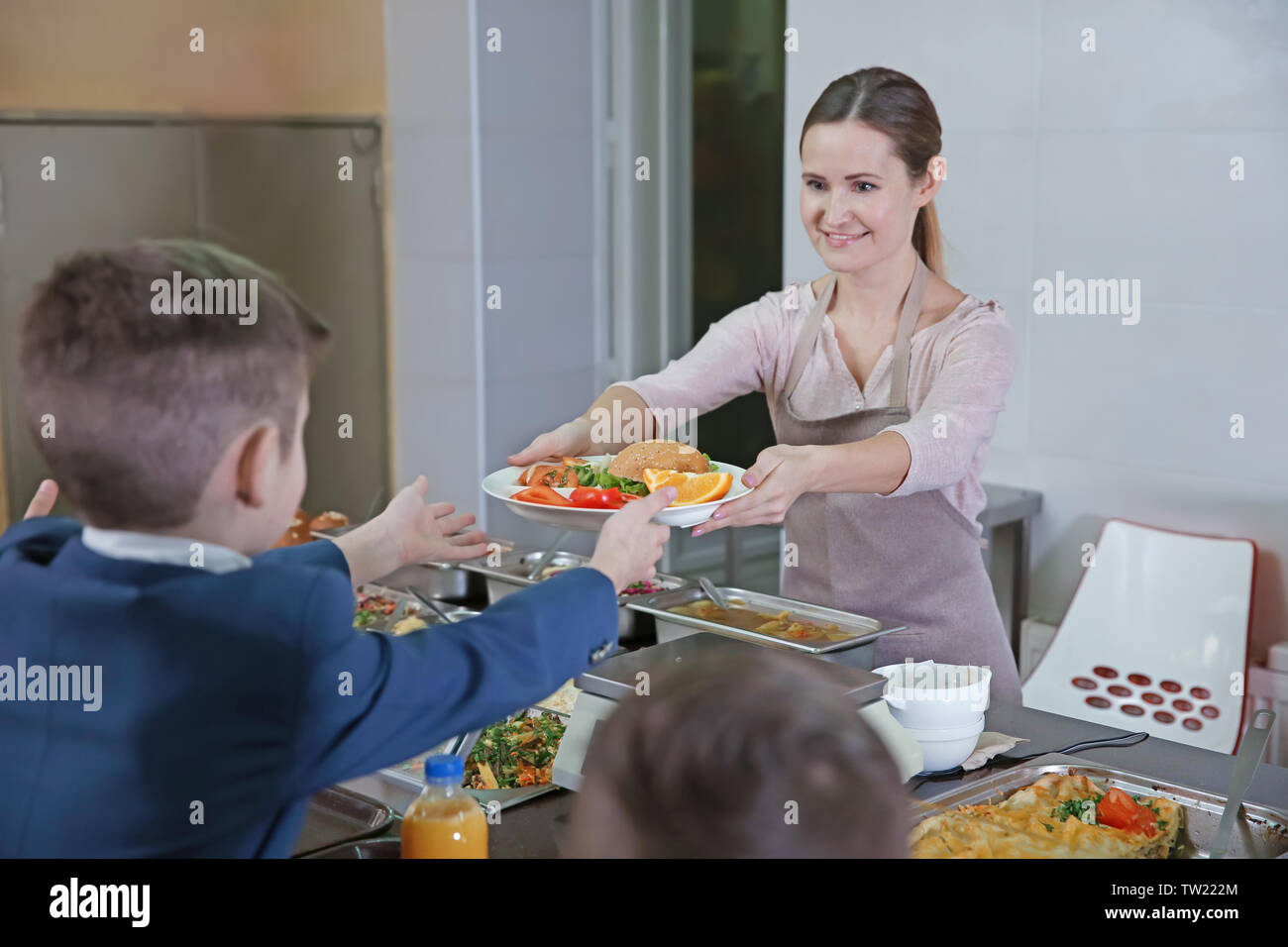 Pleasant woman giving lunch to school boy in cafeteria Stock Photo - Alamy