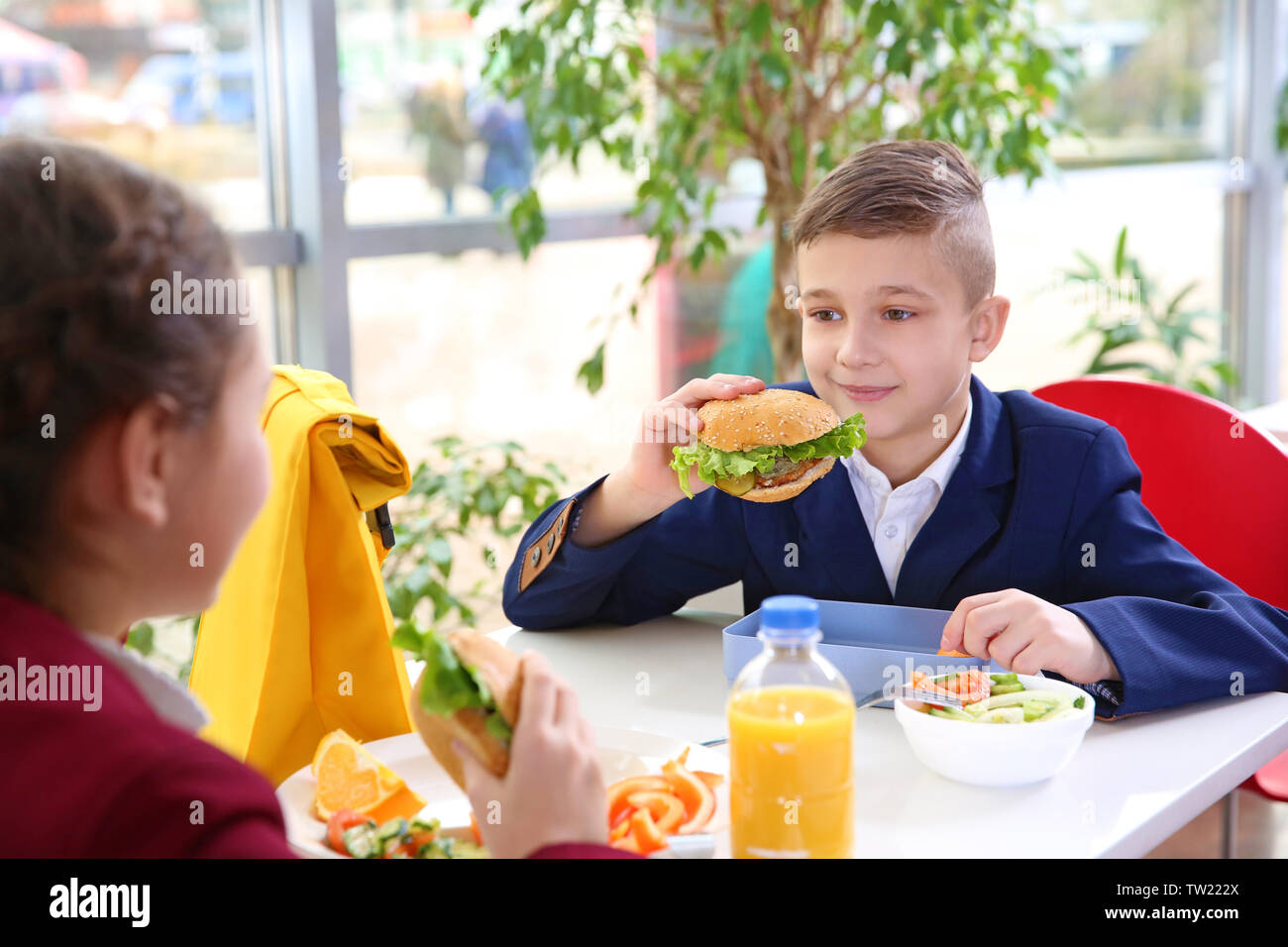 Children sitting at cafeteria table while eating lunch Stock Photo - Alamy