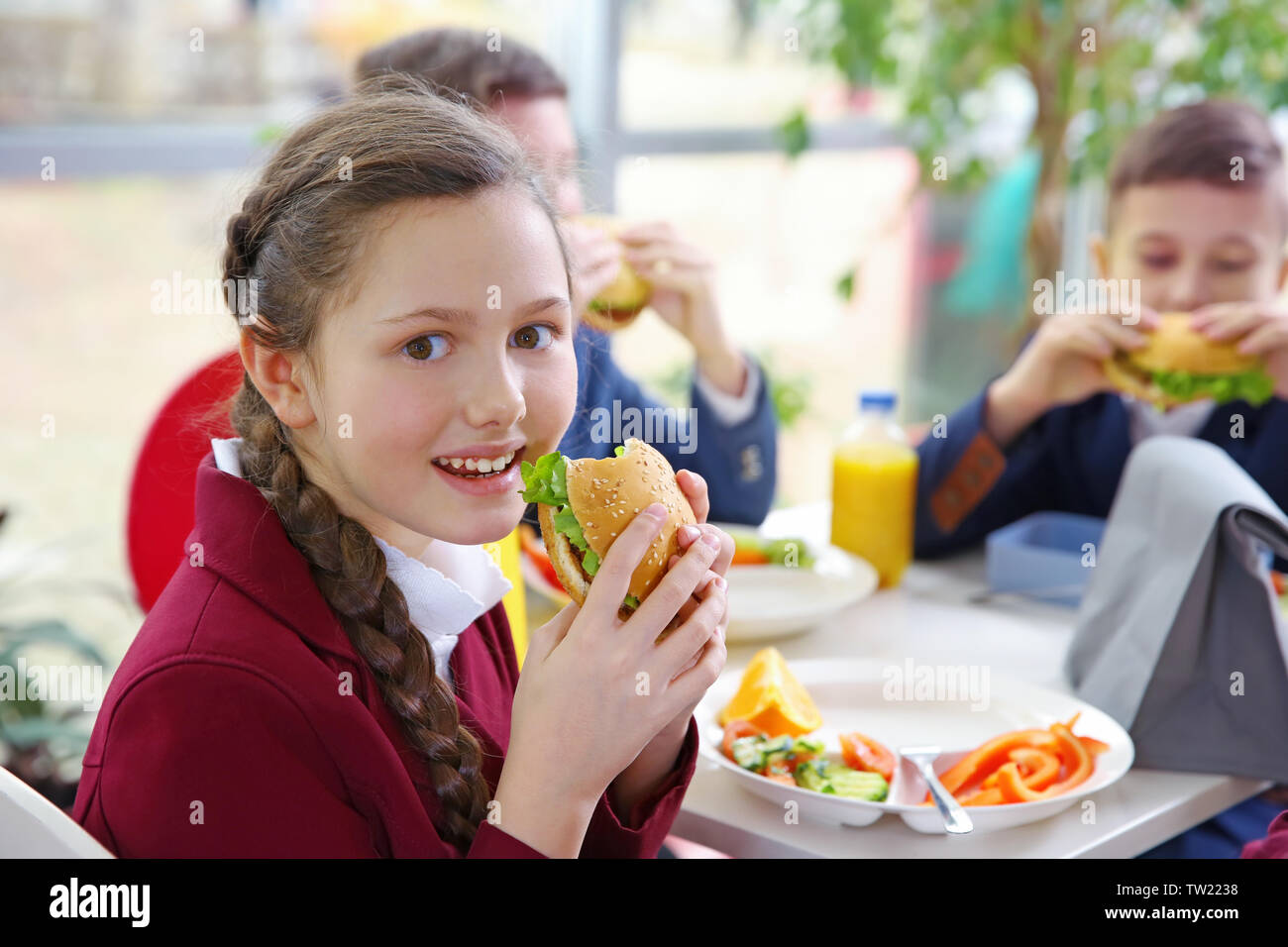 Beautiful girl eating delicious food while sitting at dining table in ...