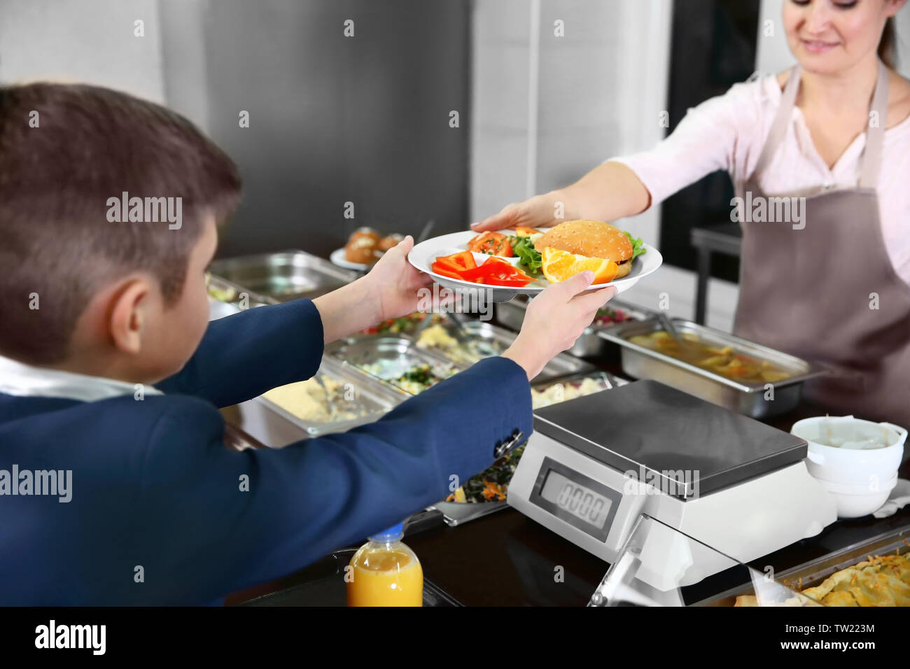Pleasant woman giving lunch to school boy in cafeteria Stock Photo - Alamy