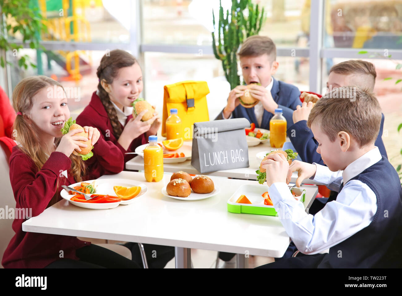Children sitting at cafeteria table while eating lunch Stock Photo - Alamy