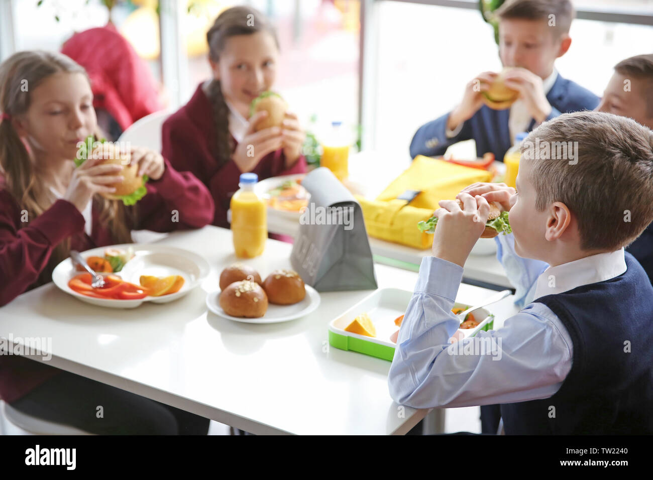 Children sitting at cafeteria table while eating lunch Stock Photo - Alamy