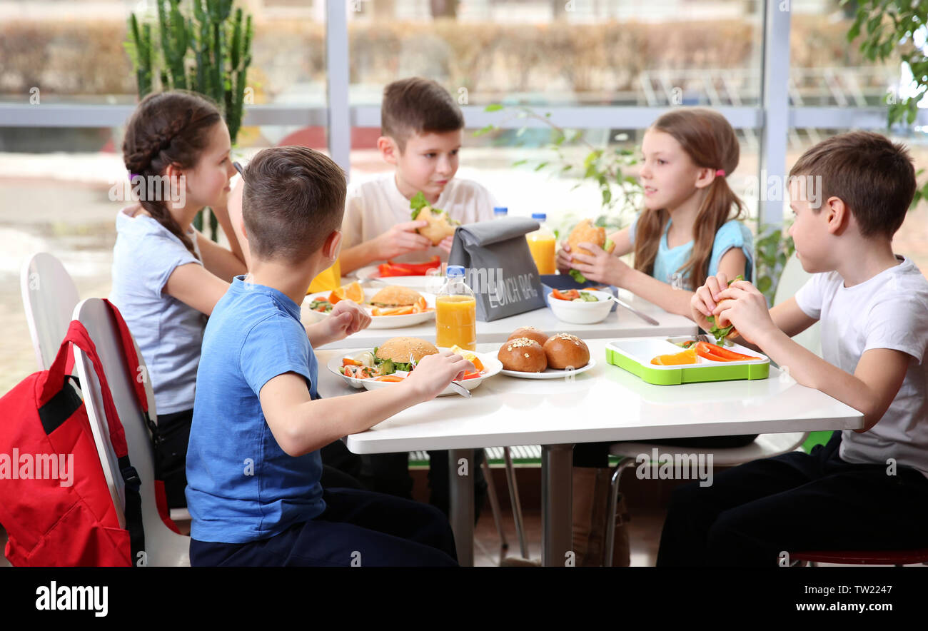 Children sitting at cafeteria table while eating lunch Stock Photo - Alamy