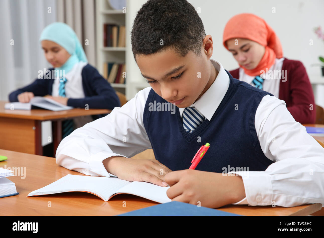 Cute boy sitting at desk in school class Stock Photo - Alamy