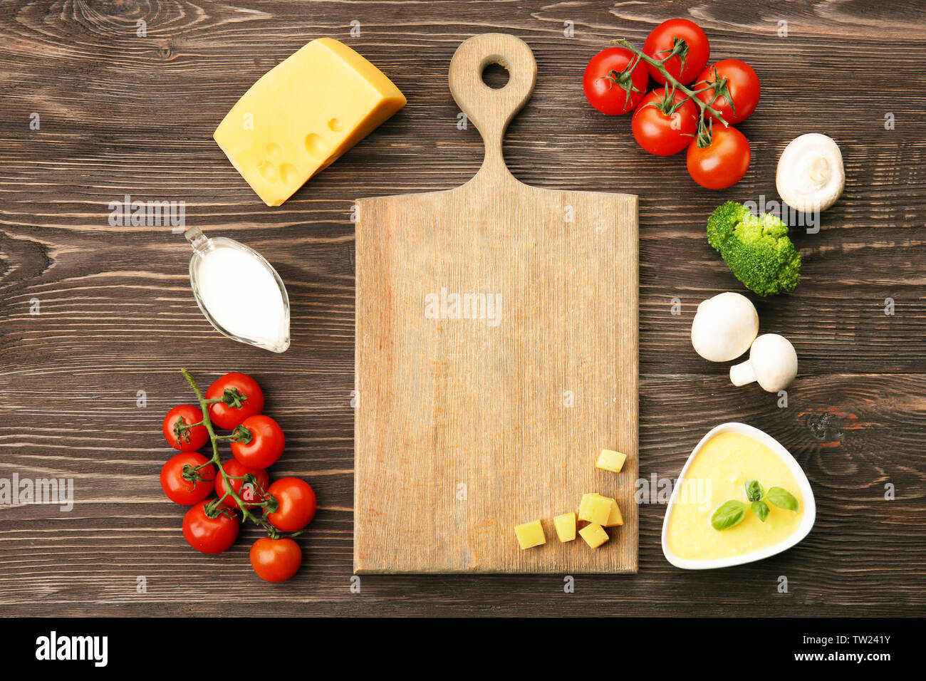 Still life with food ingredients and wooden board on table Stock Photo ...