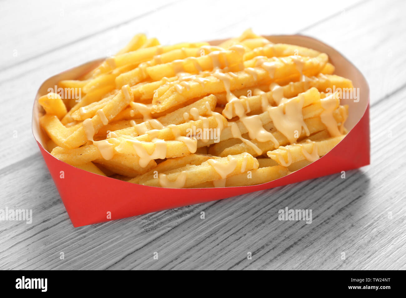Paper red box full of delicious french fries with cheese sauce on white ...