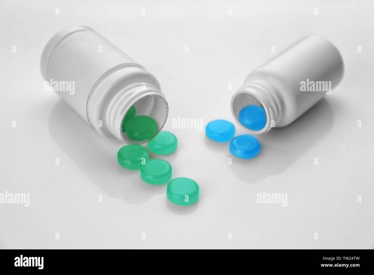 Cough drops spilling out of bottles on white background Stock Photo - Alamy