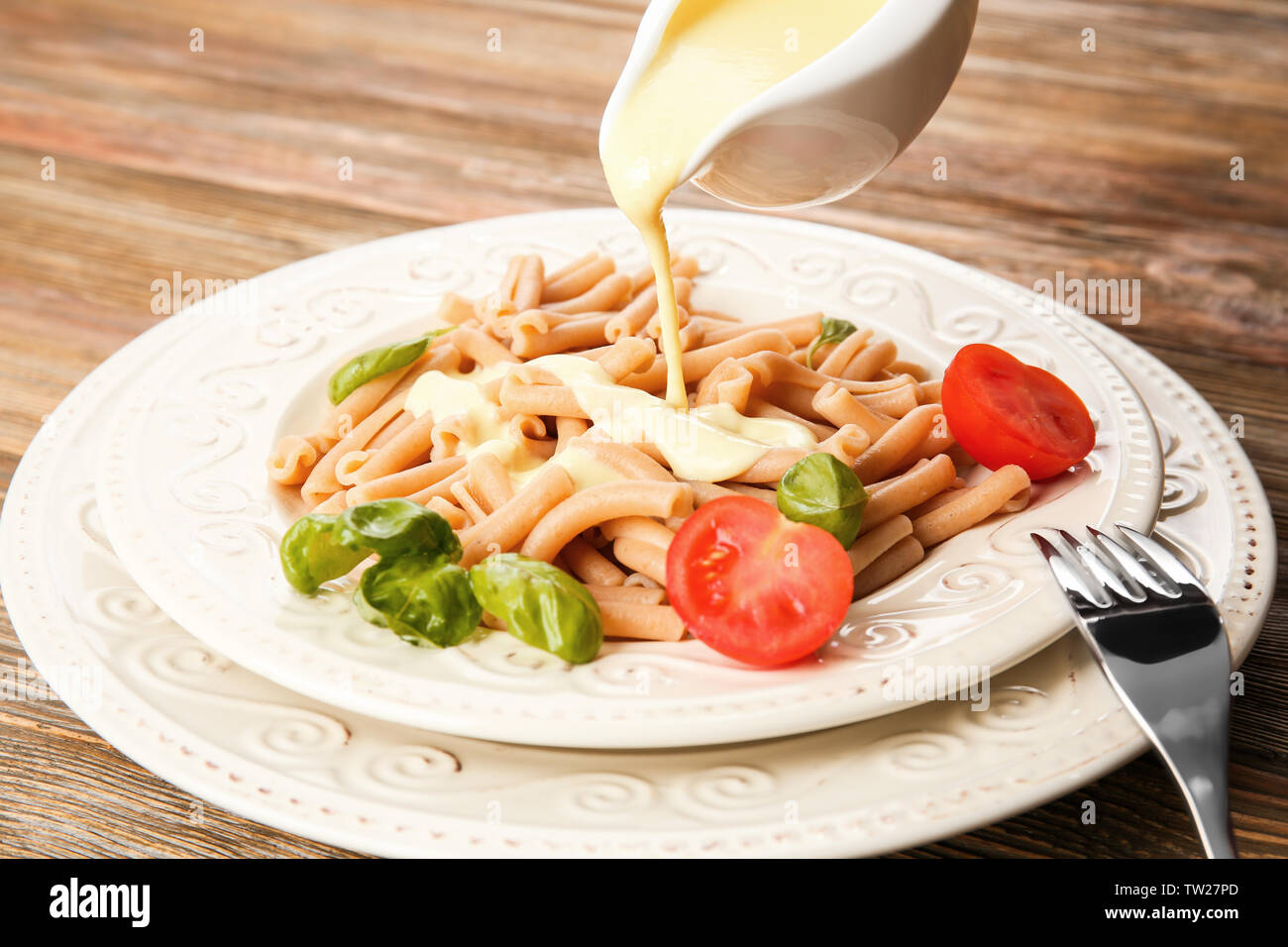 Adding cheese sauce to delicious pasta, closeup Stock Photo - Alamy