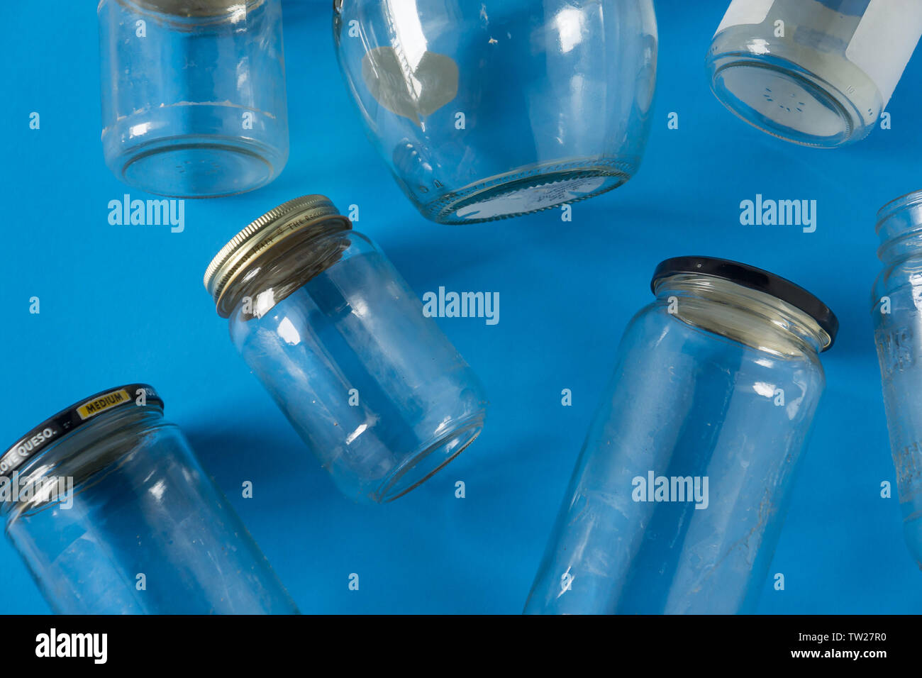 Transparent glass jars with lids isolated on blue background, top view ...