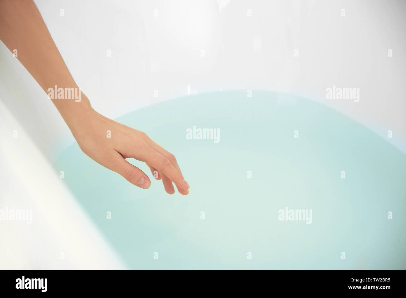 Female hand determining temperature of water in bathtub Stock Photo - Alamy