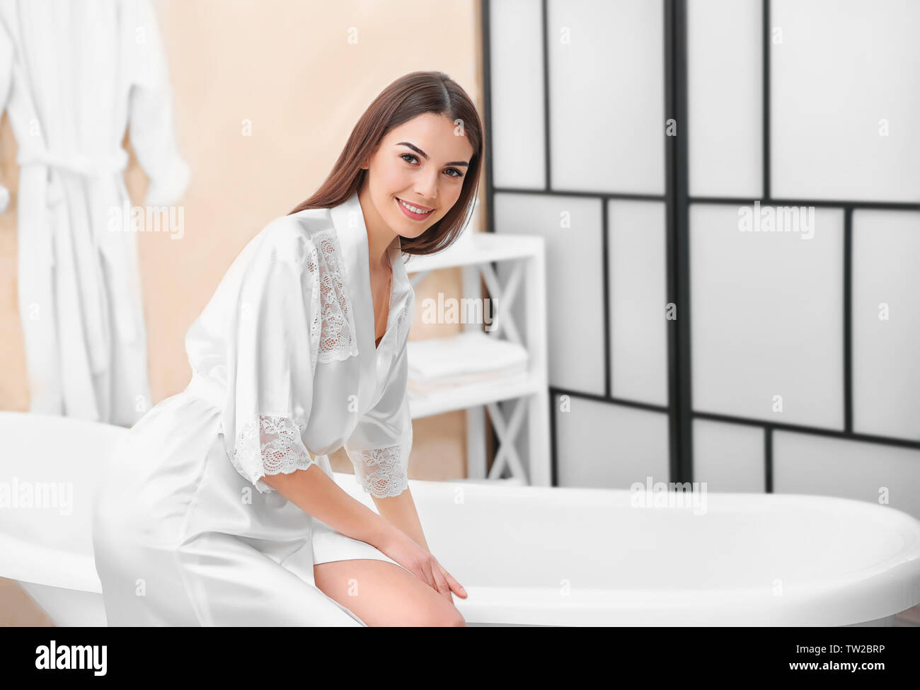 Beautiful young woman in dressing-gown going to take a bath at home ...