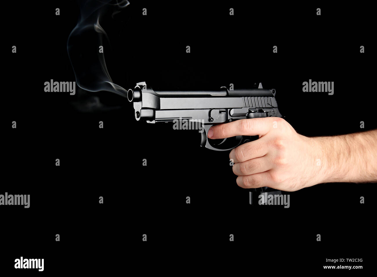 Male hand holding smoking gun on black background Stock Photo - Alamy