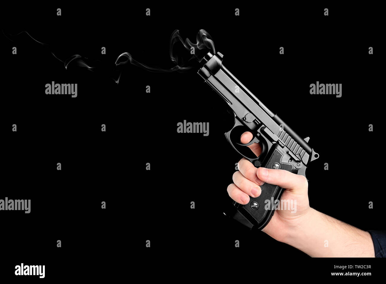 Male hand holding smoking gun on black background Stock Photo - Alamy