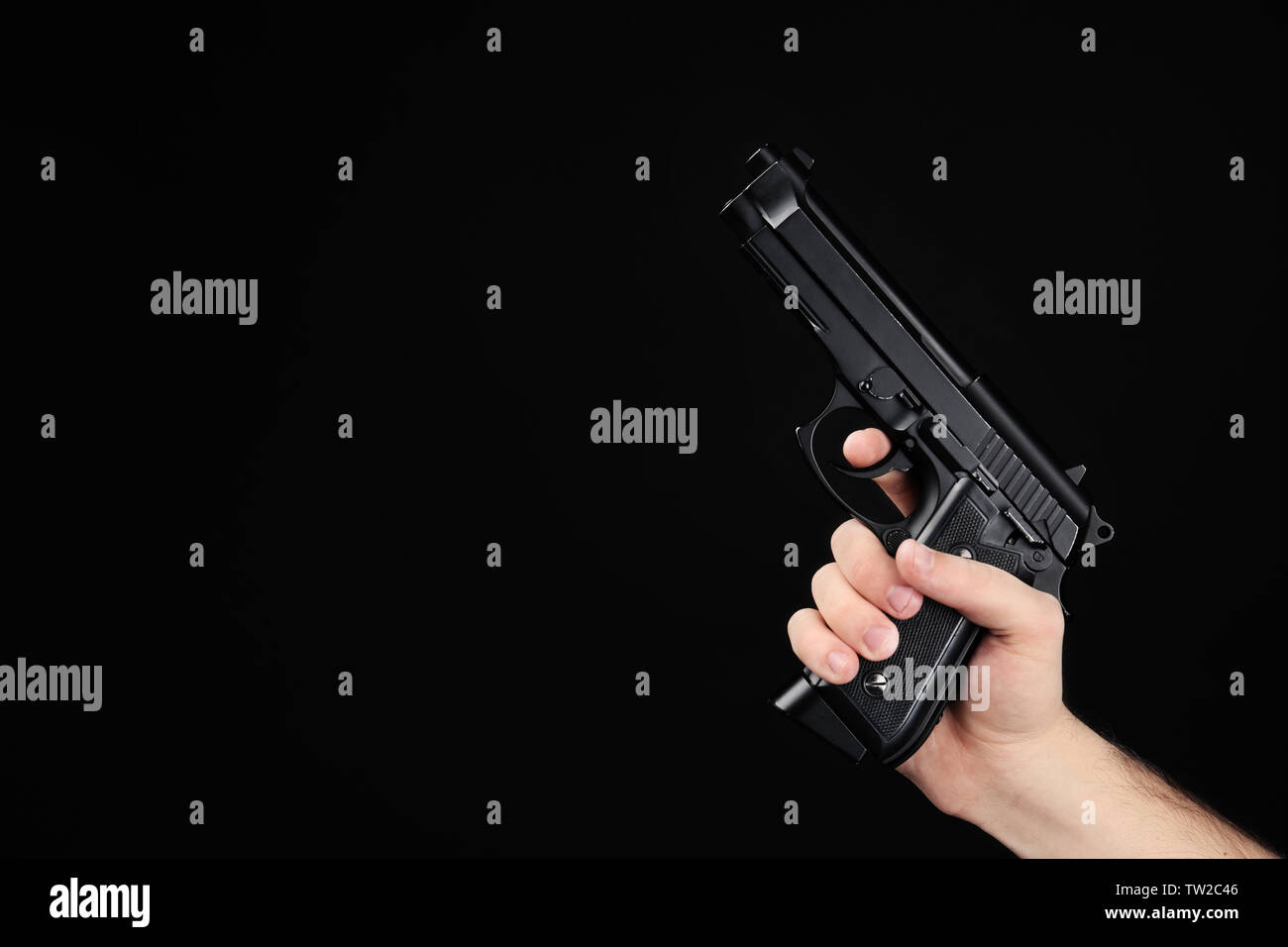 Male hand holding gun on black background Stock Photo - Alamy