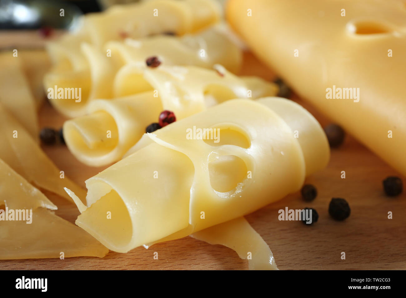 Rolled slices of cheese on wooden board Stock Photo - Alamy