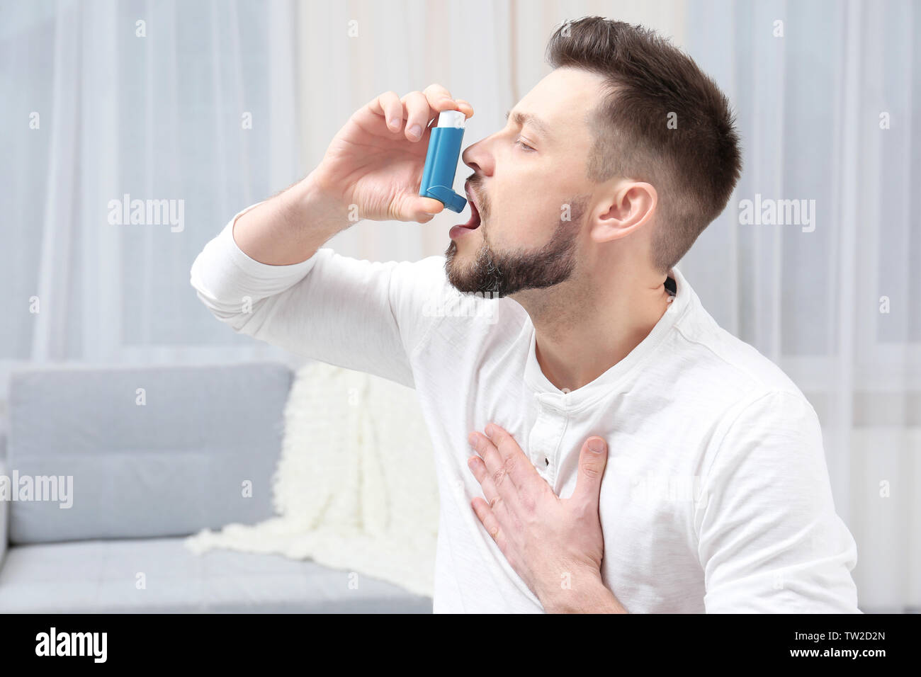 Young man using asthma inhaler at home Stock Photo - Alamy