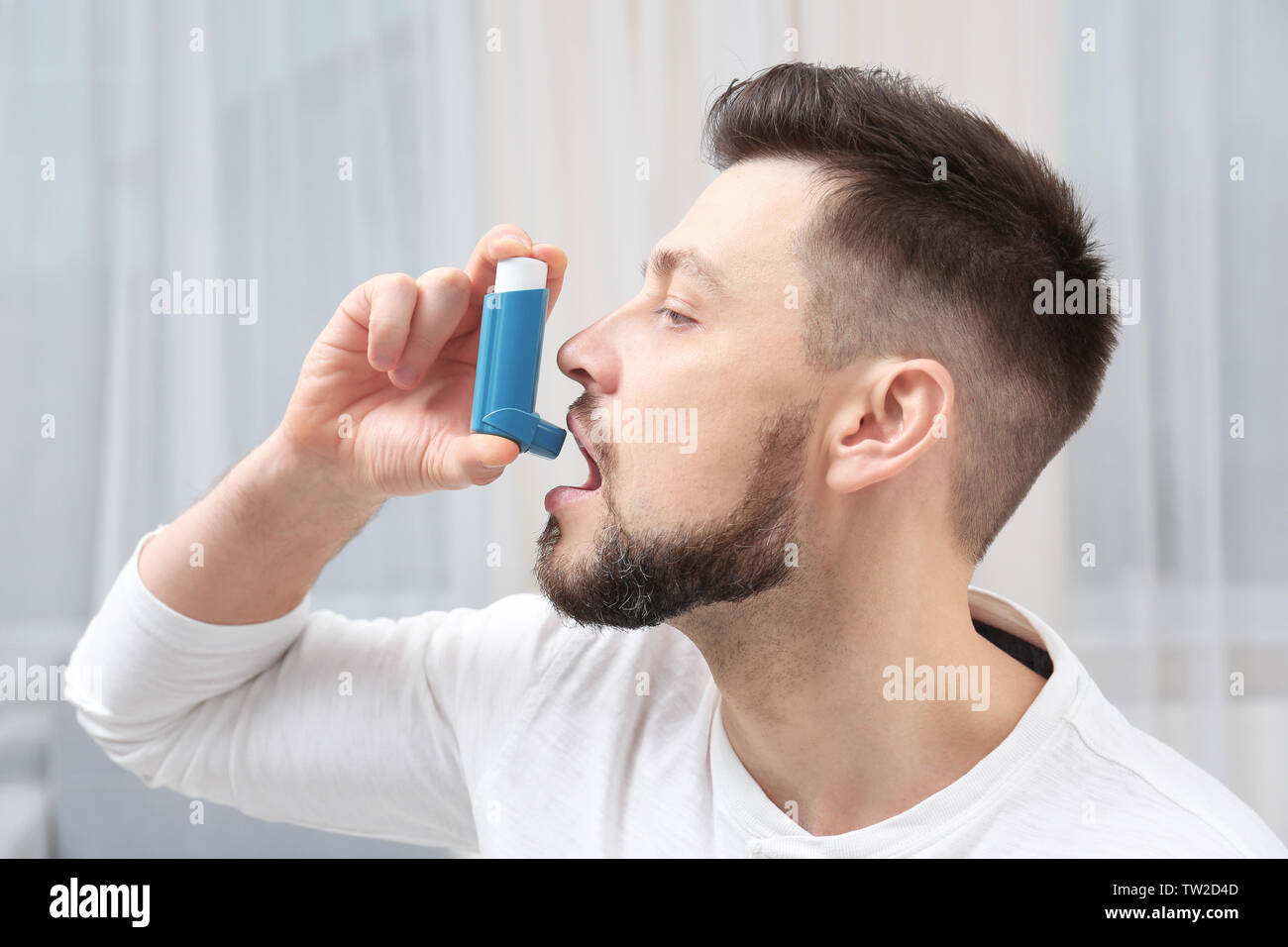 Young man using asthma inhaler at home Stock Photo - Alamy