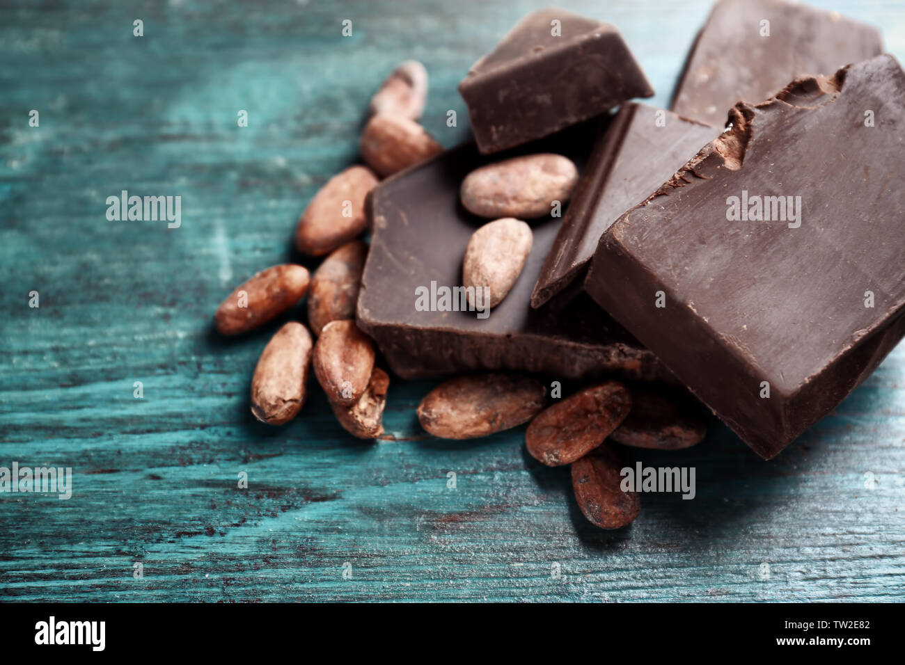Broken chocolate pieces and cocoa beans on color background Stock Photo ...