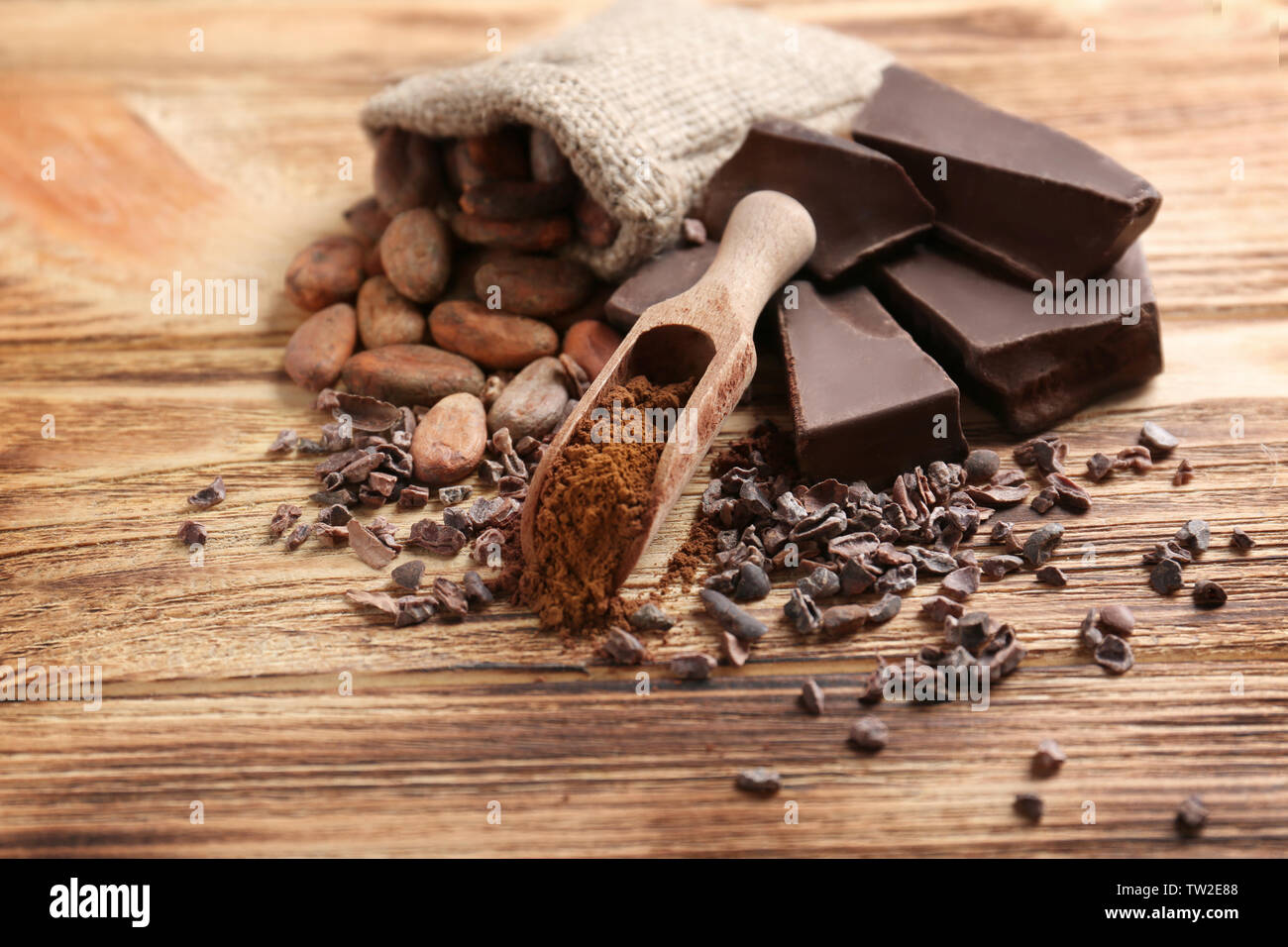 Broken chocolate pieces, beans and scoop with cocoa powder on wooden ...