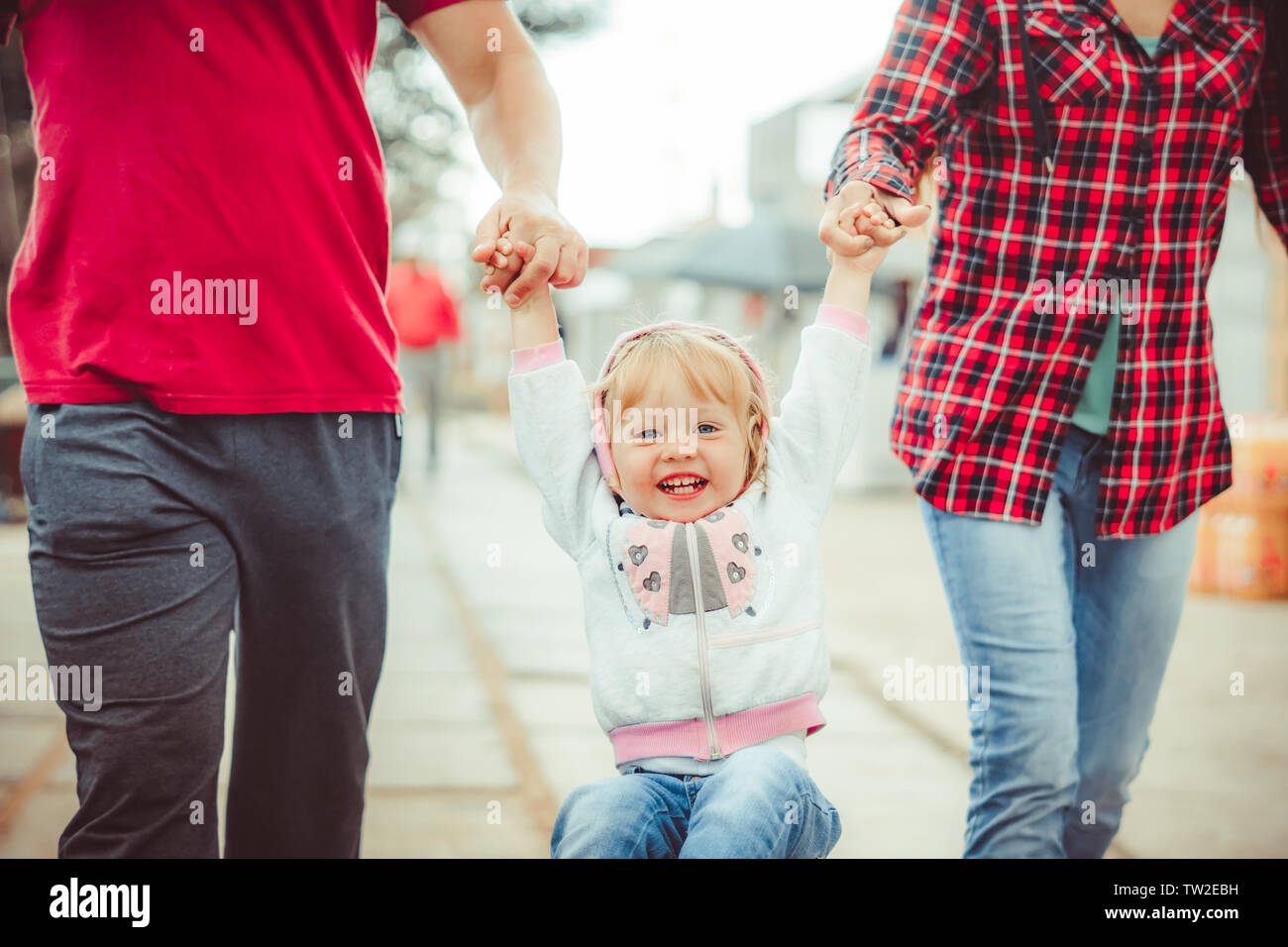 parents walk with child holding hands child laughs Stock Photo - Alamy