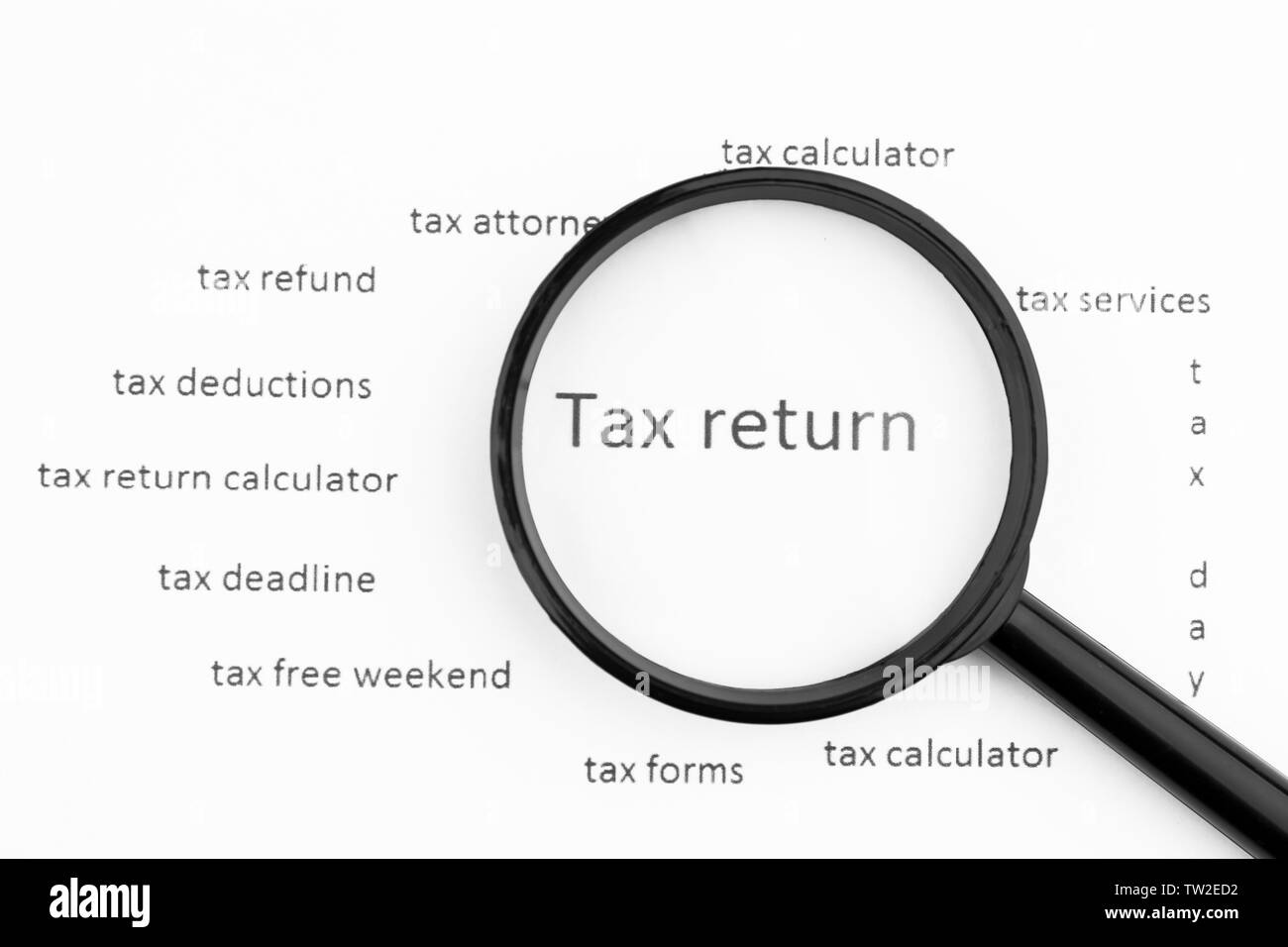TAX RETURN text printed on paper and hand glass Stock Photo - Alamy