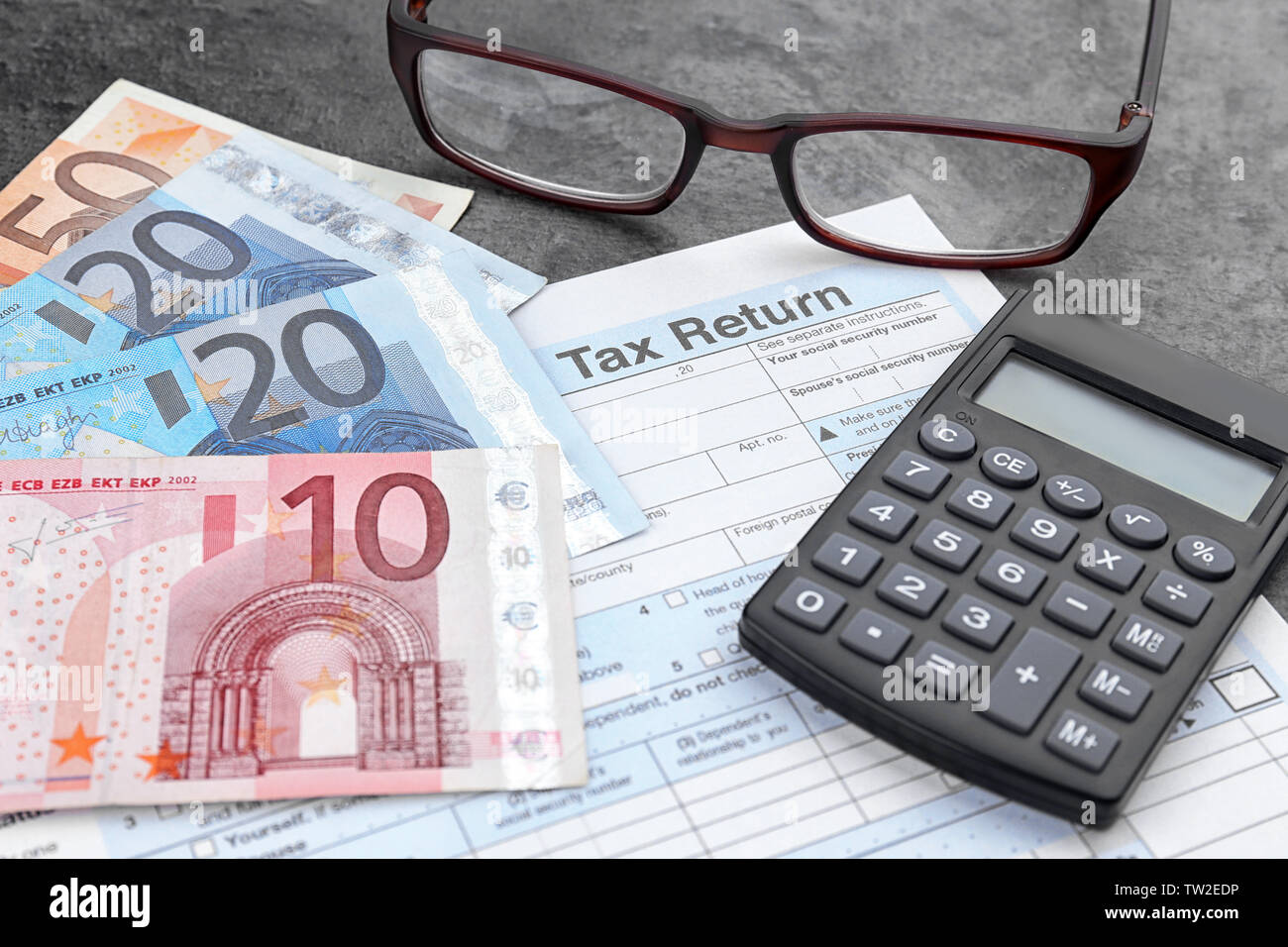 Tax return form, glasses, calculator and euro on table Stock Photo - Alamy