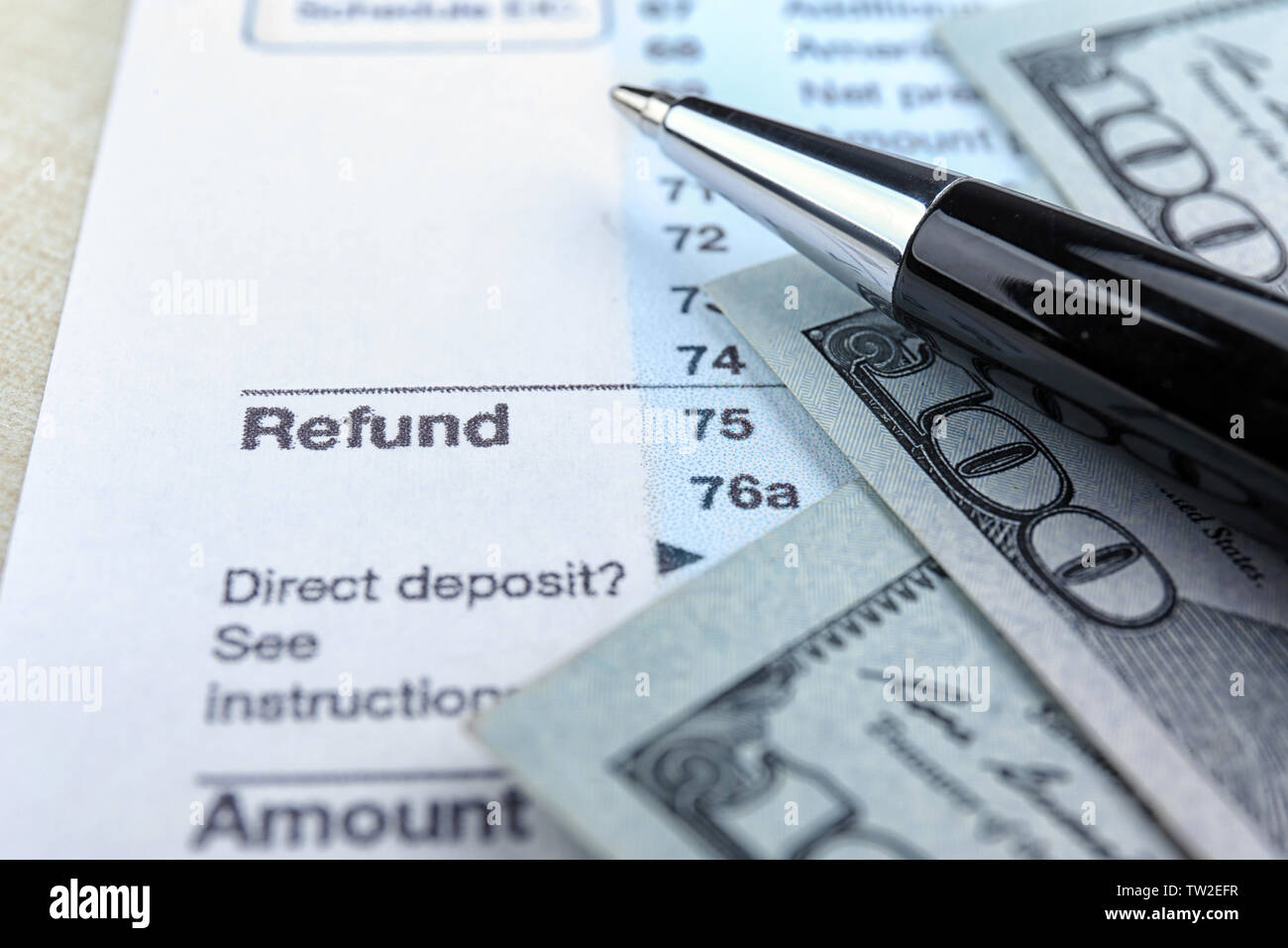 Tax refund document, pen and dollars on table Stock Photo - Alamy