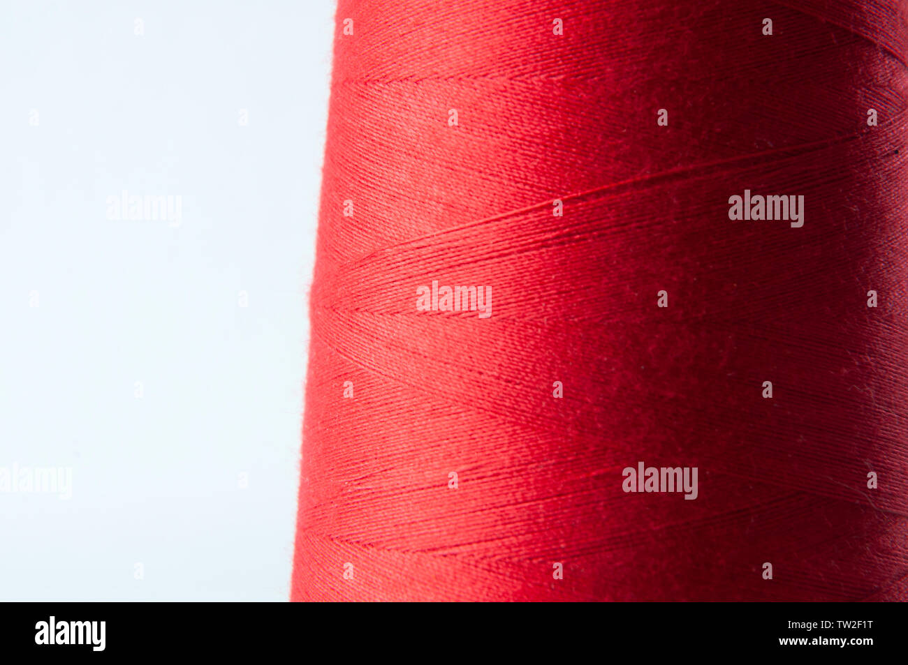 close-up of sewing thread on yarn spool in front of white background ...