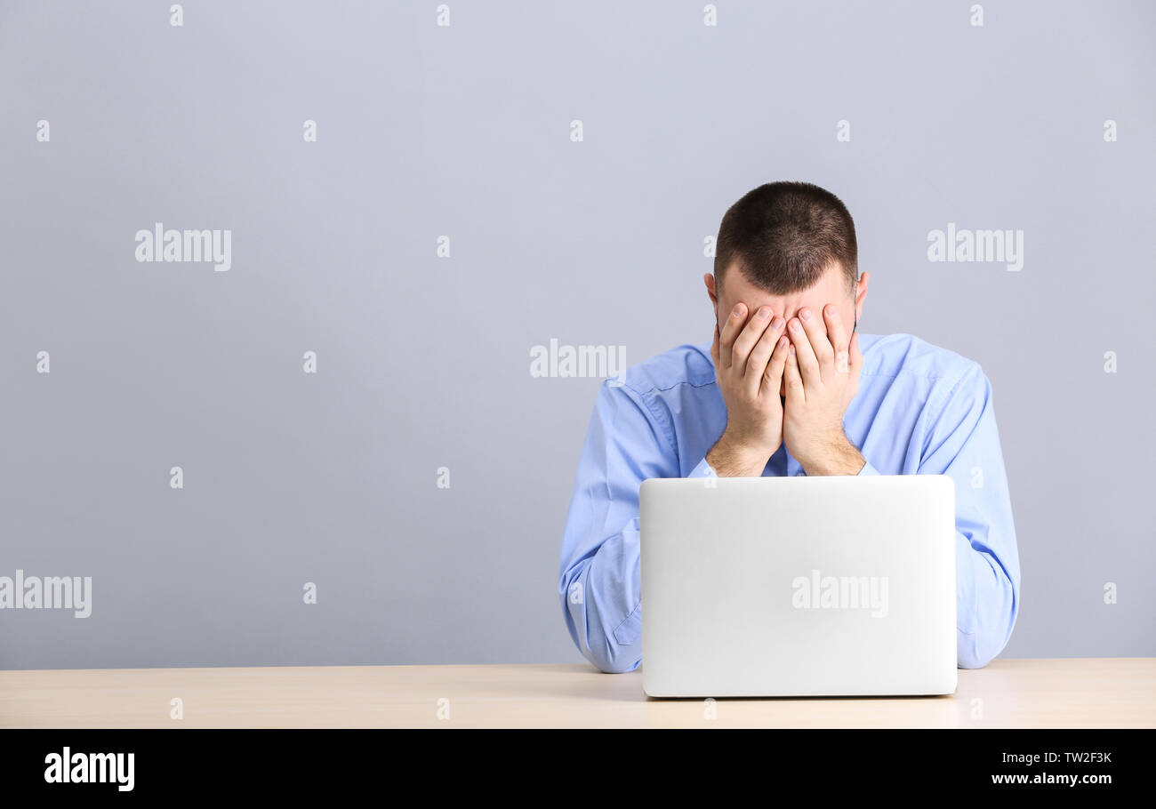 Handsome young man suffering from headache while working with laptop ...