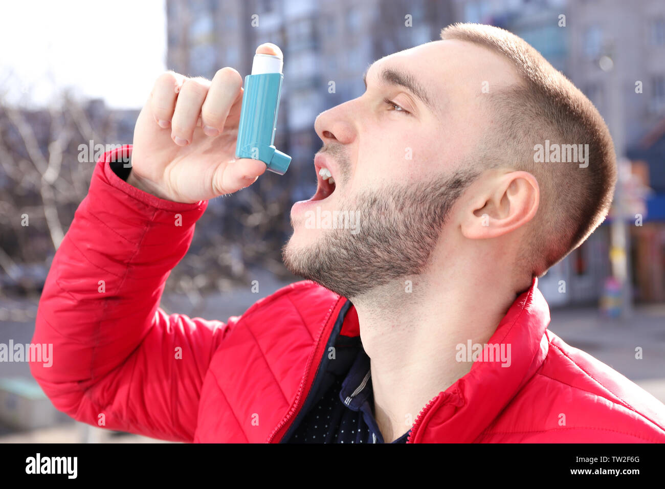 Young man using asthma inhaler on street Stock Photo - Alamy
