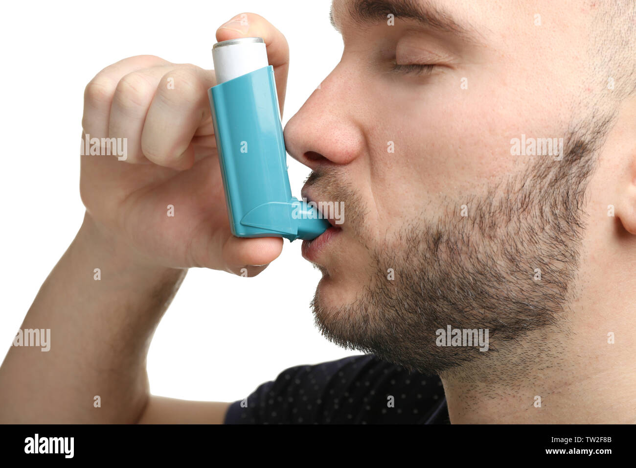 Young man using asthma inhaler on white background Stock Photo - Alamy