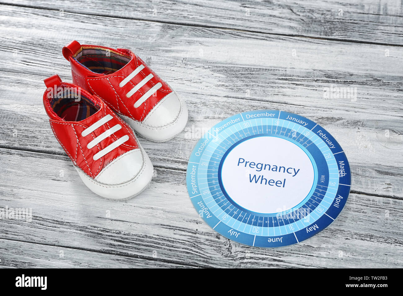 Pregnancy wheel with baby booties on wooden background Stock Photo - Alamy