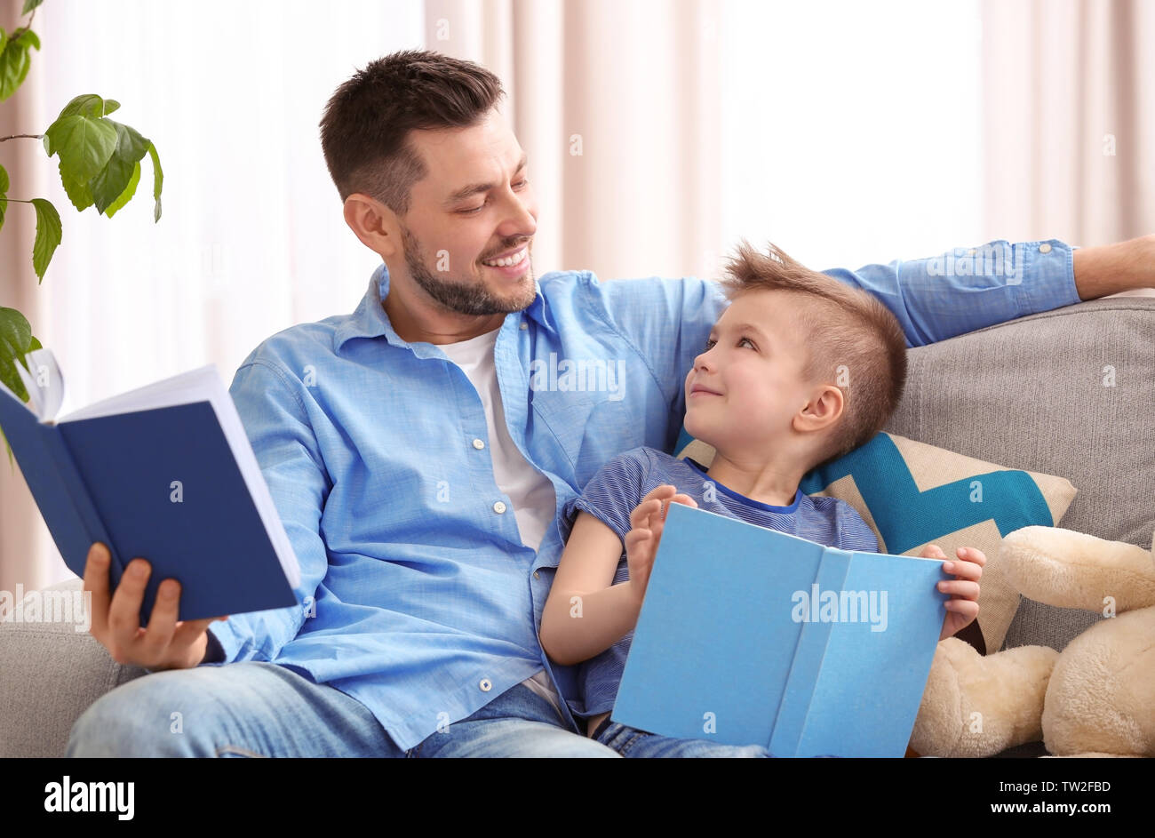 Dad and son reading interesting books at home Stock Photo - Alamy