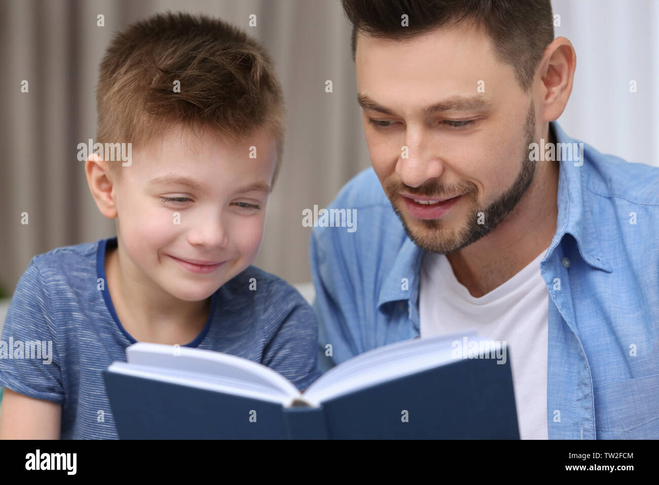 Dad and son reading interesting book at home Stock Photo - Alamy
