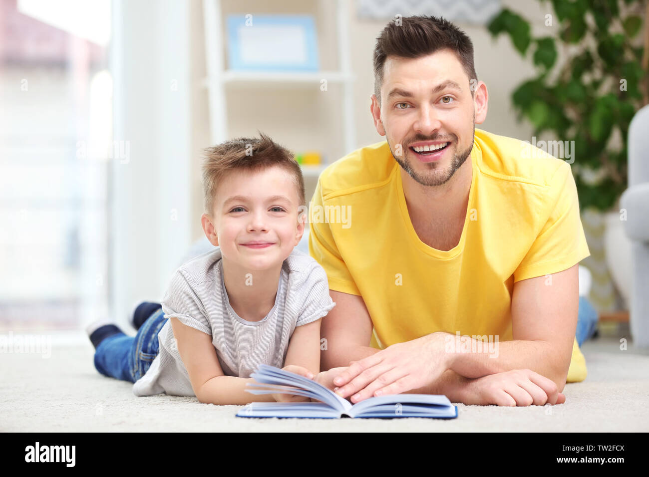 Dad and son reading interesting book at home Stock Photo - Alamy