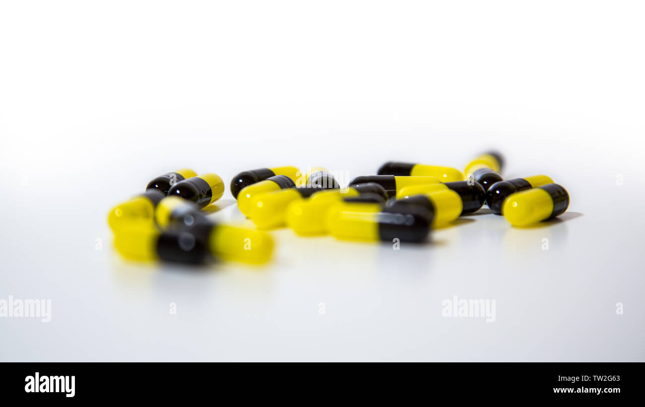 Close up of many black and yellow pills and tablets medicine isolated ...