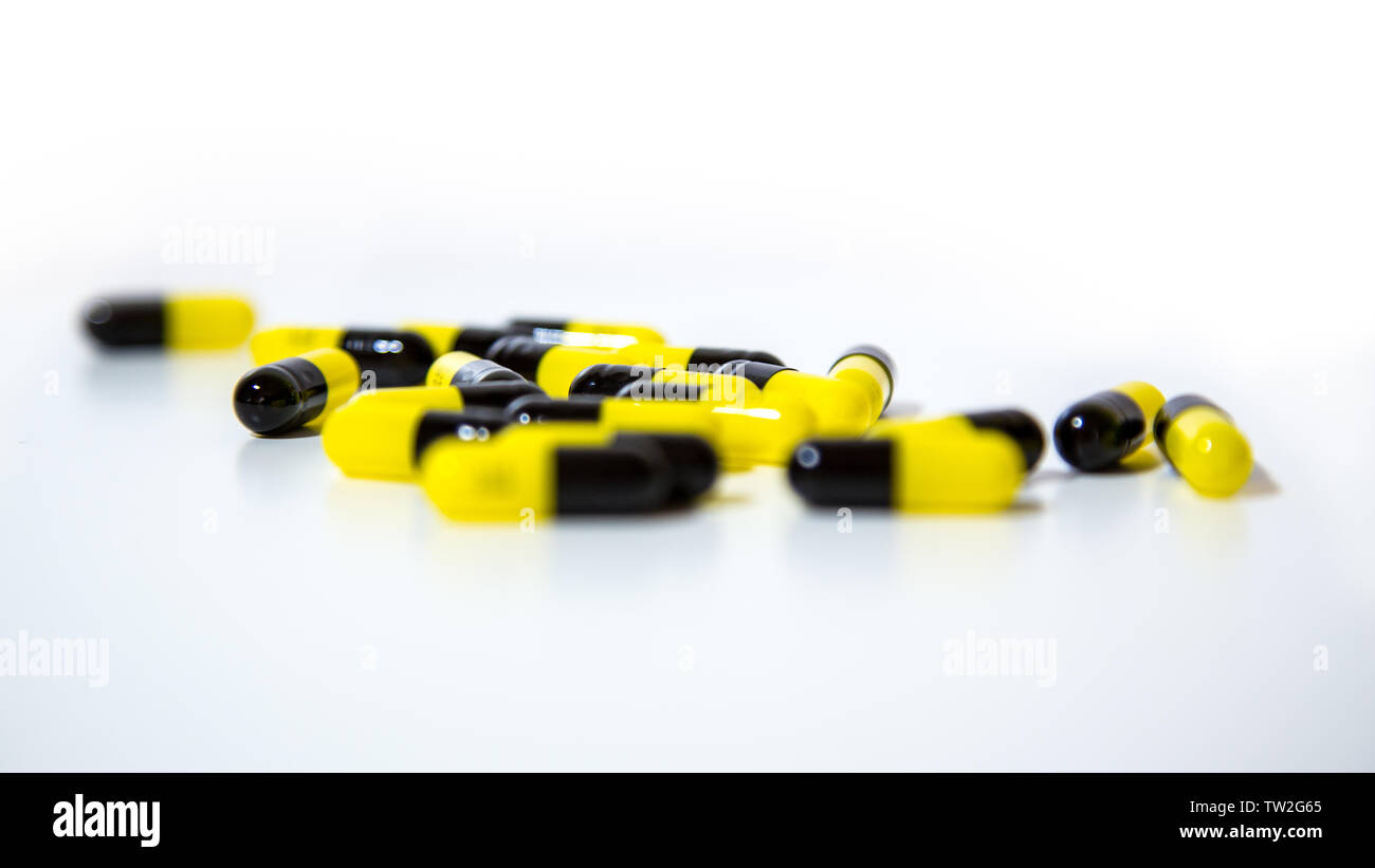 Close up of many black and yellow pills and tablets medicine isolated ...
