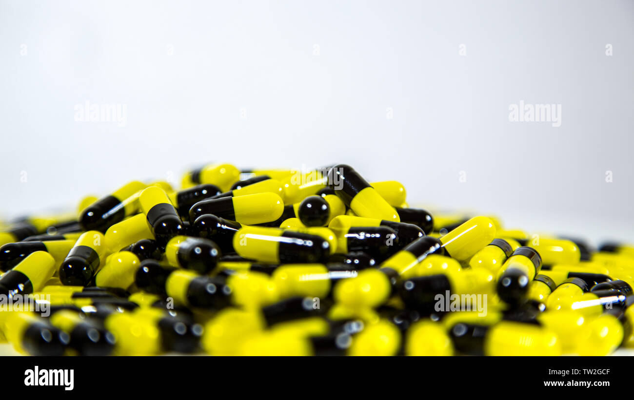 Close up of many black and yellow pills and tablets medicine isolated ...