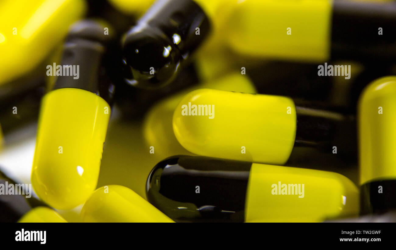 Close up of many black and yellow pills and tablets medicine isolated ...
